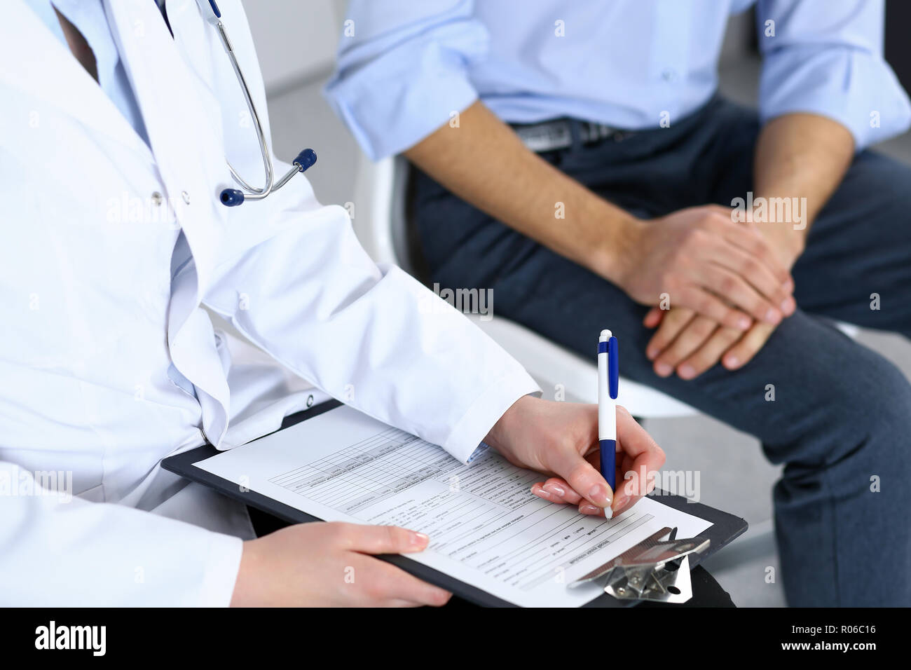 Female doctor holding application form while consulting man patient in ...