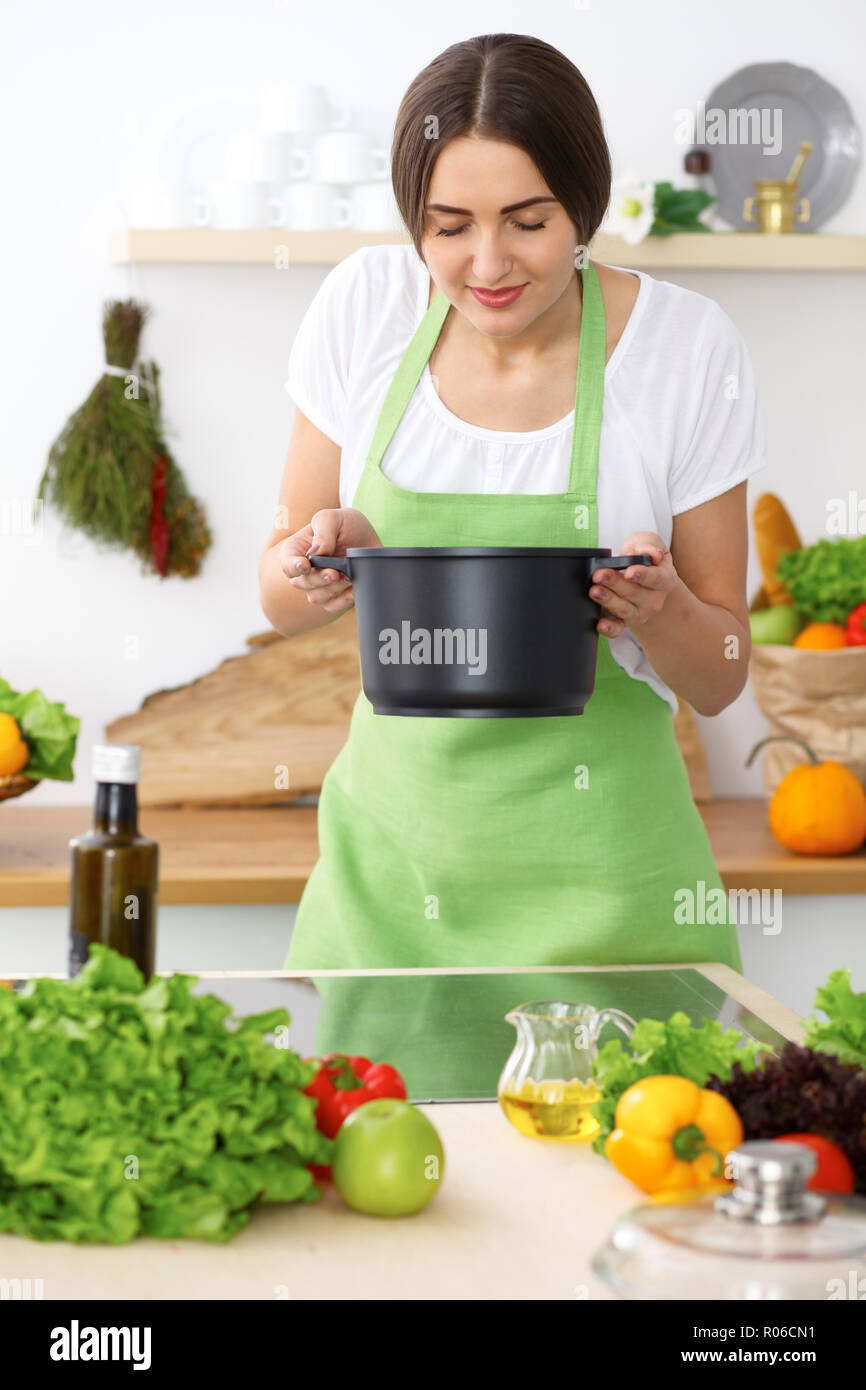 Beautiful Hispanic woman cooking soup in kitchen. Healthy meal and ...