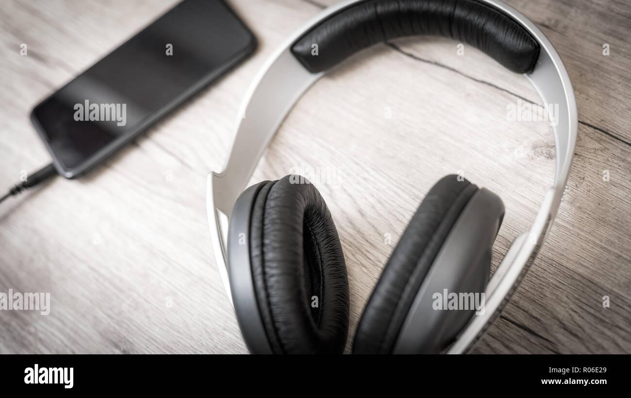 Silver headphones and smart phone on wooden table Stock Photo - Alamy