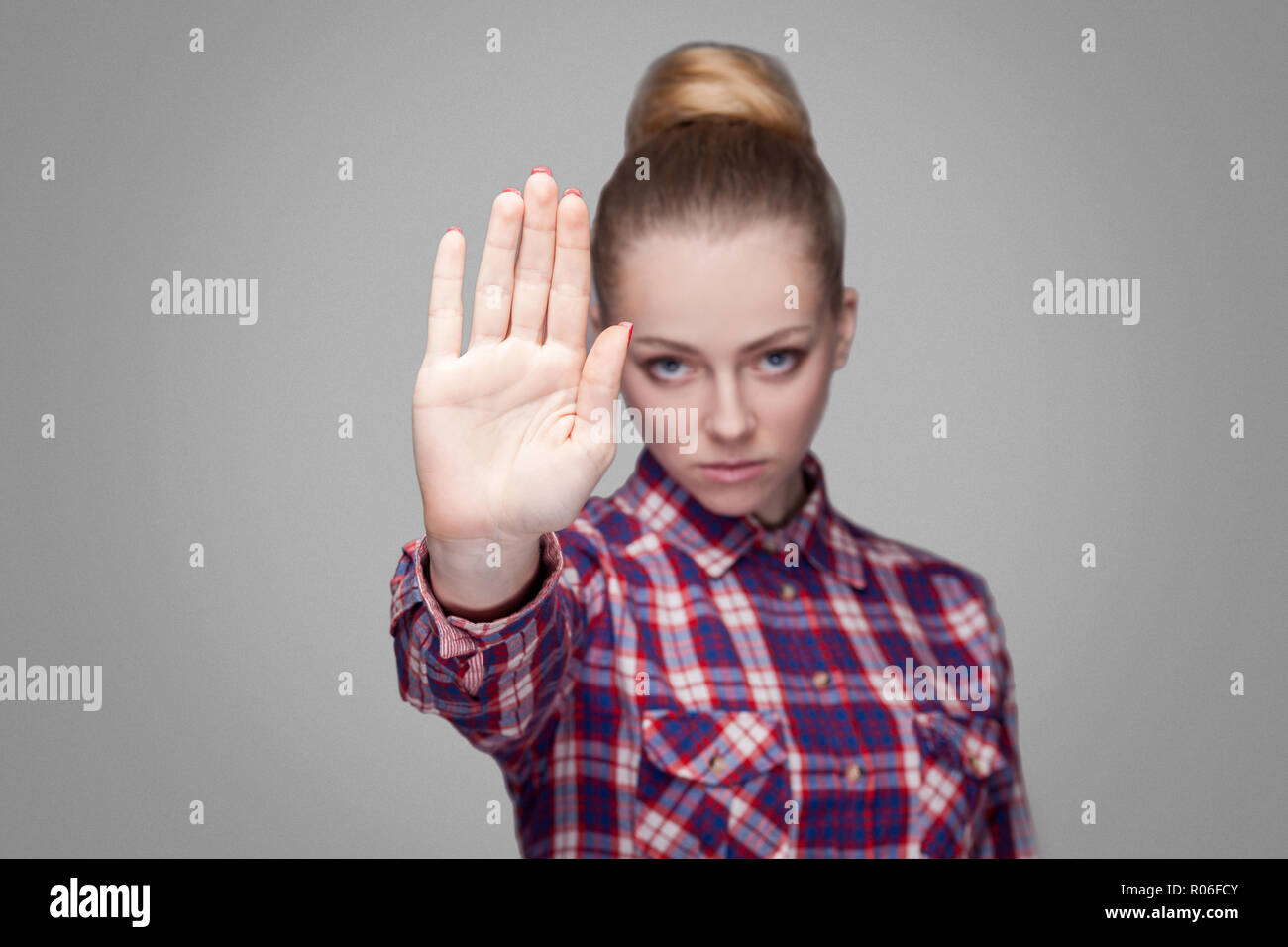 Stop it. angry girl in pink checkered shirt, collected bun hairstyle ...