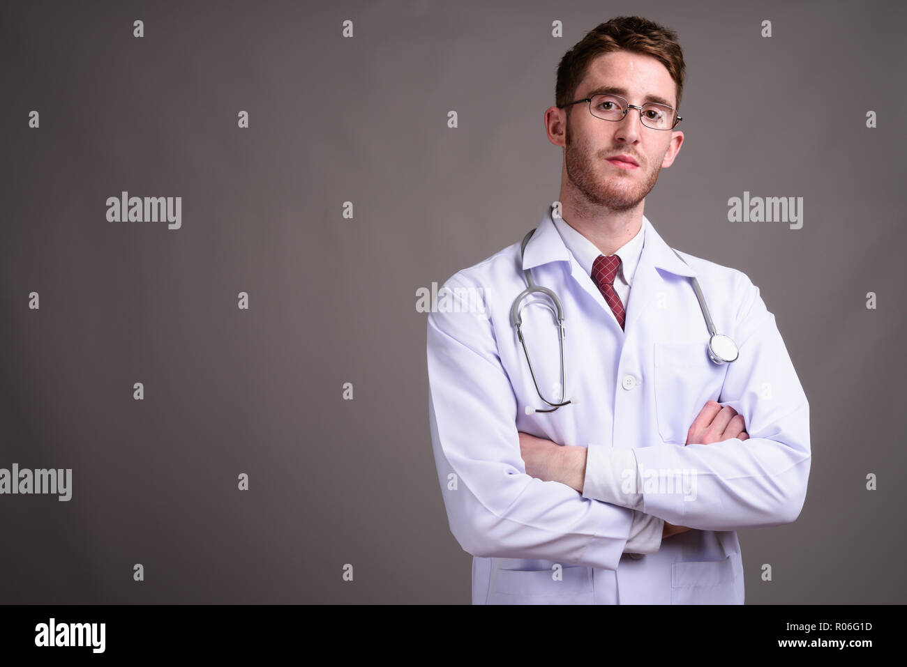 Young handsome man doctor wearing eyeglasses against gray backgr Stock ... Young handsome man doctor wearing eyeglasses against gray backgr Stock ...