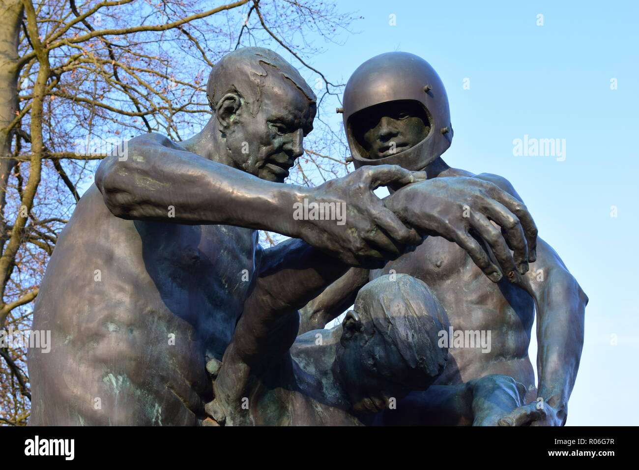 A bronze statue under blue sky during winter in a War Cemetery depicts ...