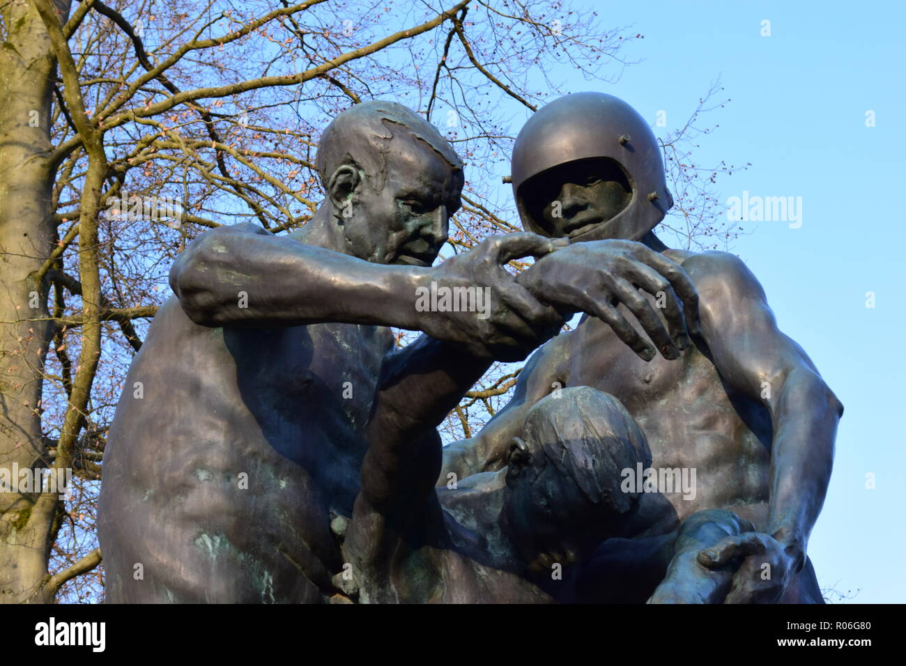 A bronze statue under blue sky during winter in a War Cemetery depicts ...