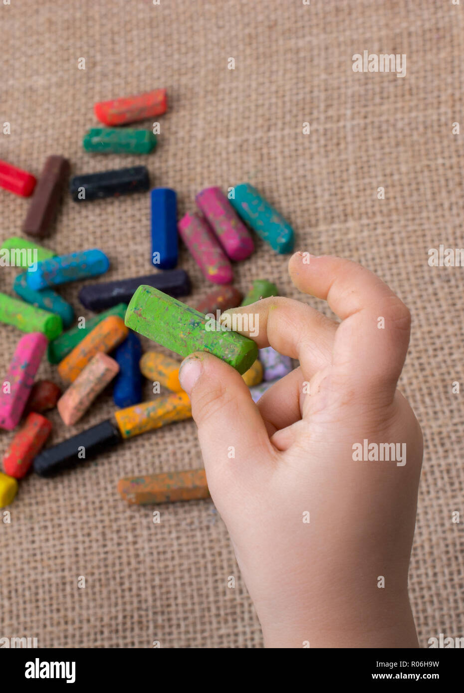 Used color crayons and a toddlers hand holding one Stock Photo - Alamy