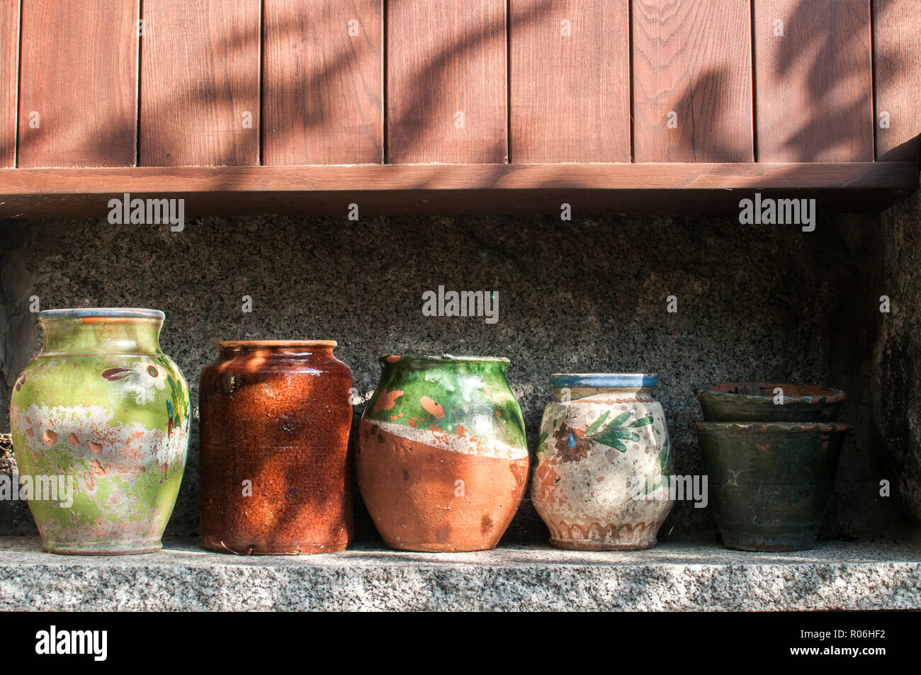 Various ceramic pots next to each other in a row in stone niche on ...