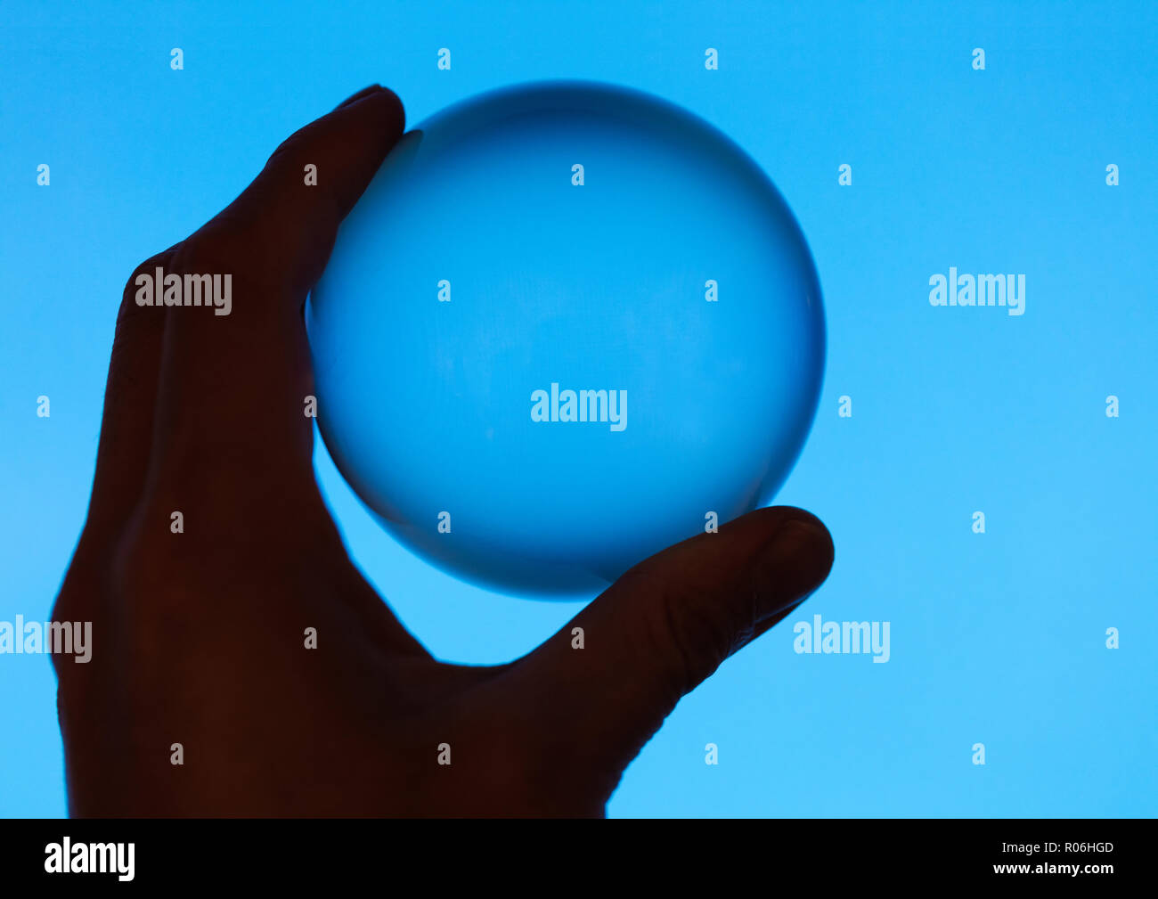Hand holding a crystal ball with blue background Stock Photo - Alamy