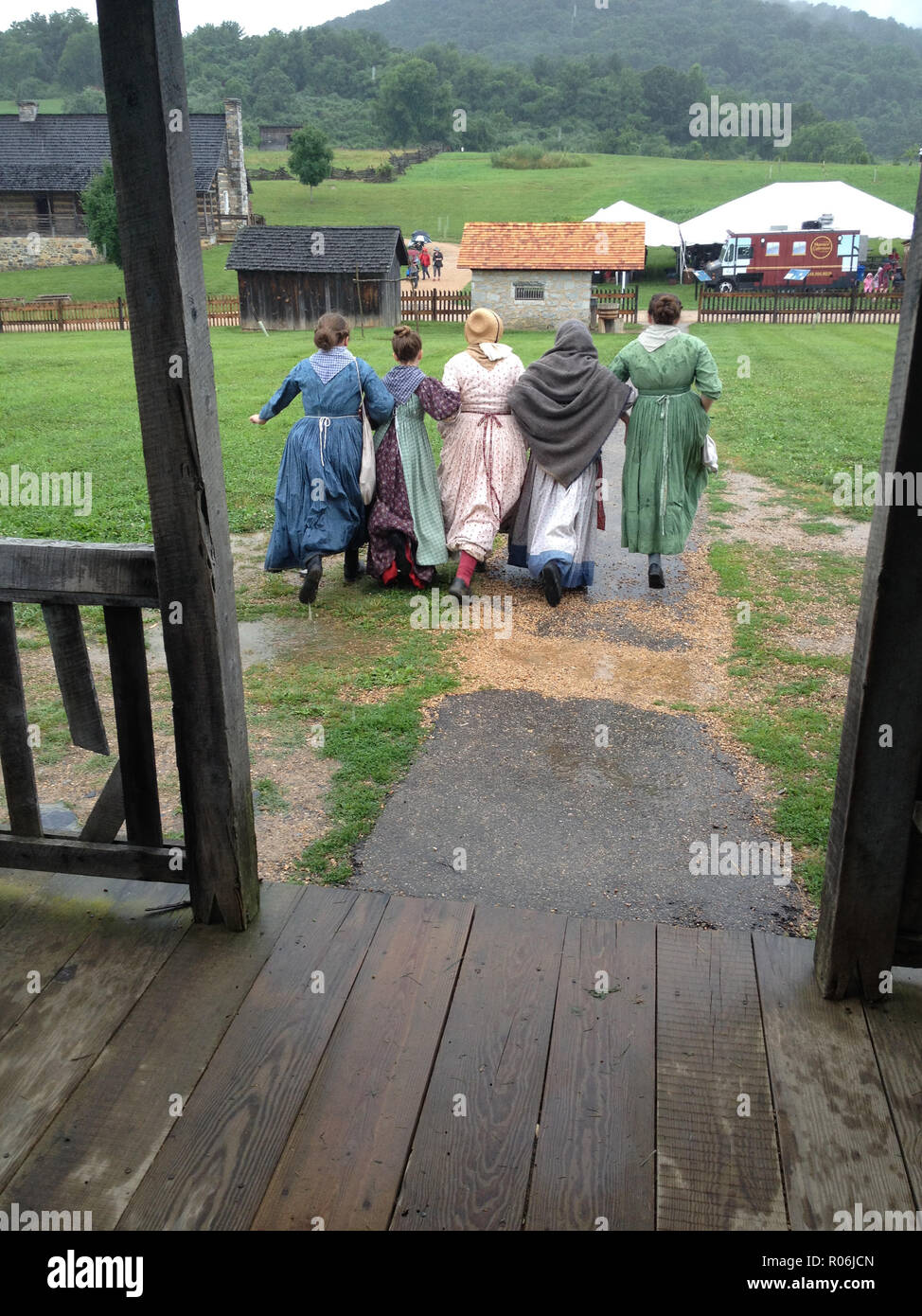 Group of young girls in colonial attire skipping in the rain ...
