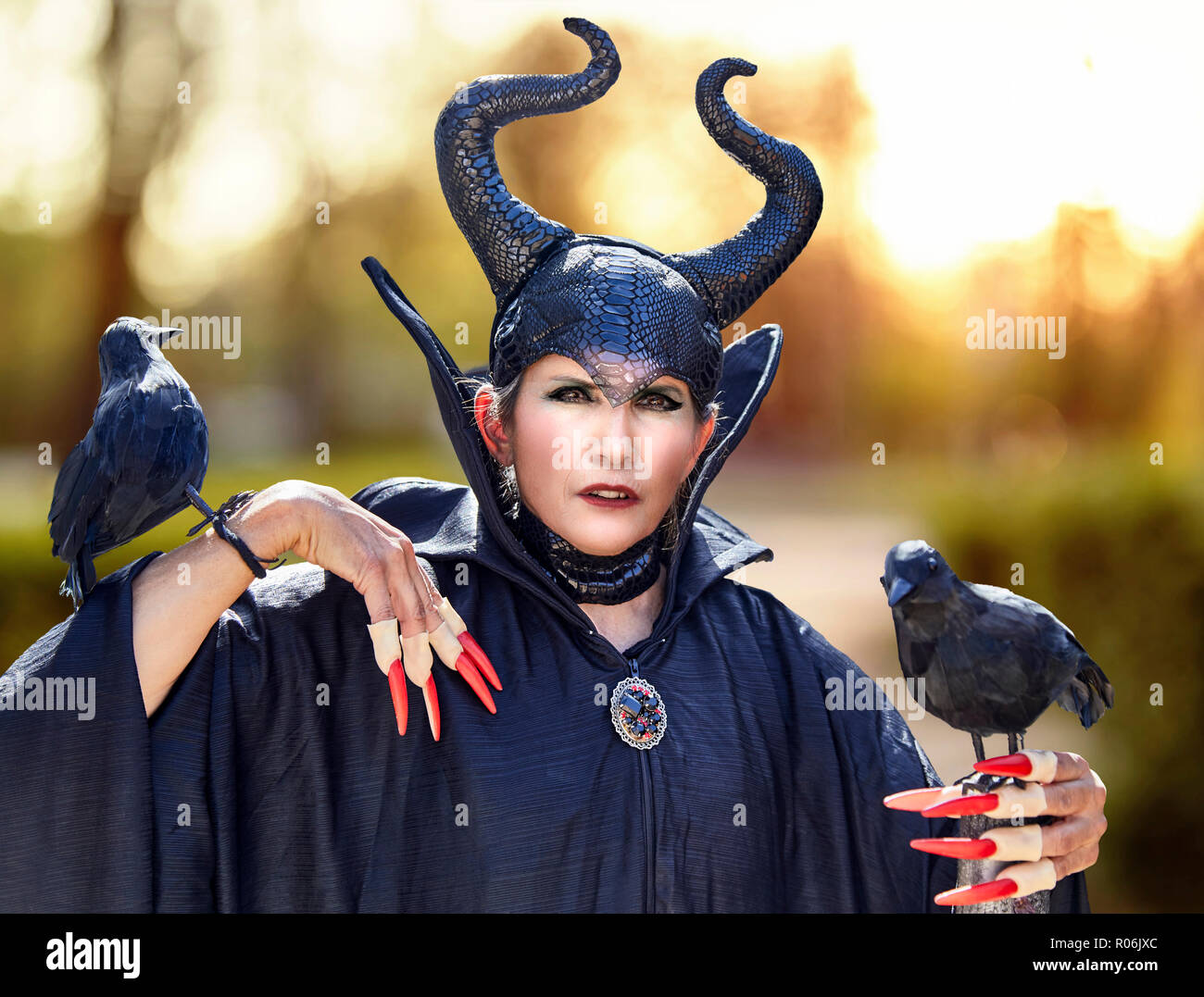 Attractive woman in a halloween costume as a wizard with fake birds and ...