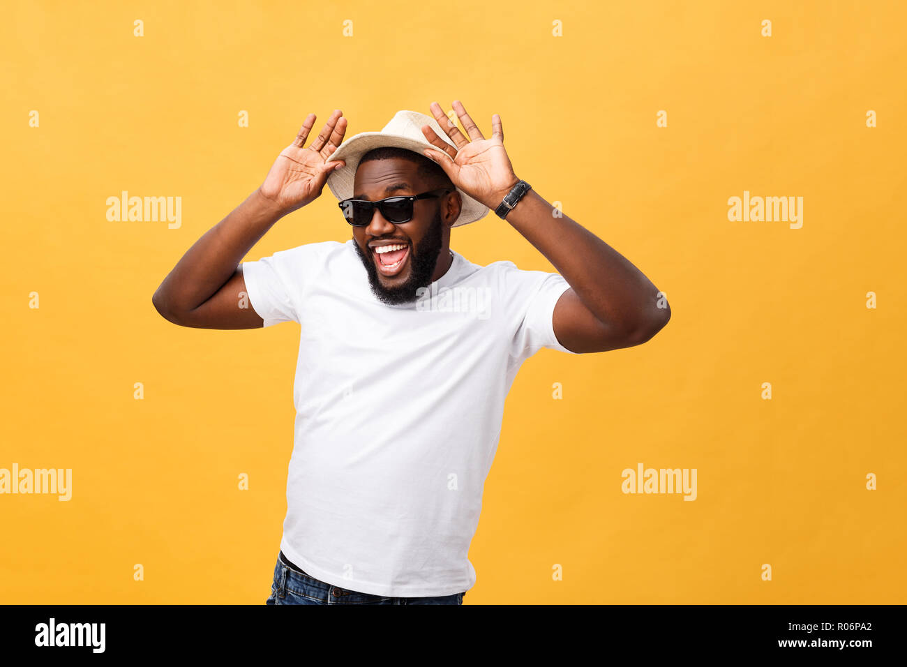 Close up portrait of a young man laughing with hands holding hat ...