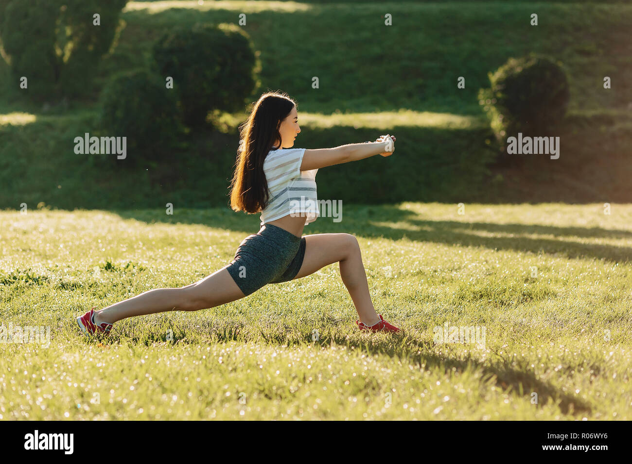 cozy fitness girl making morning stretching exercises outside on ...