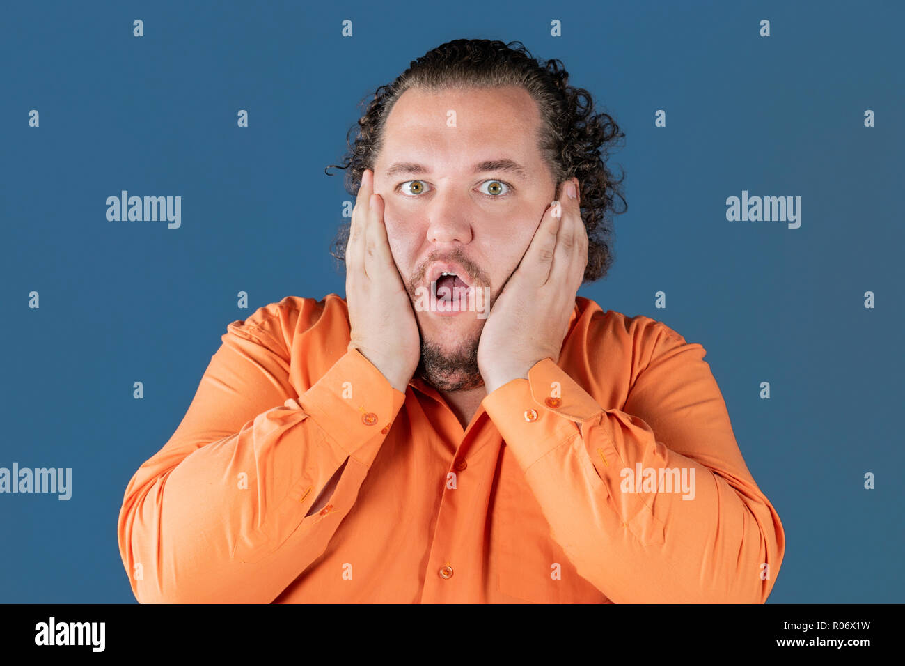 Fat man in orange shirt holds his hands over his face Stock Photo - Alamy