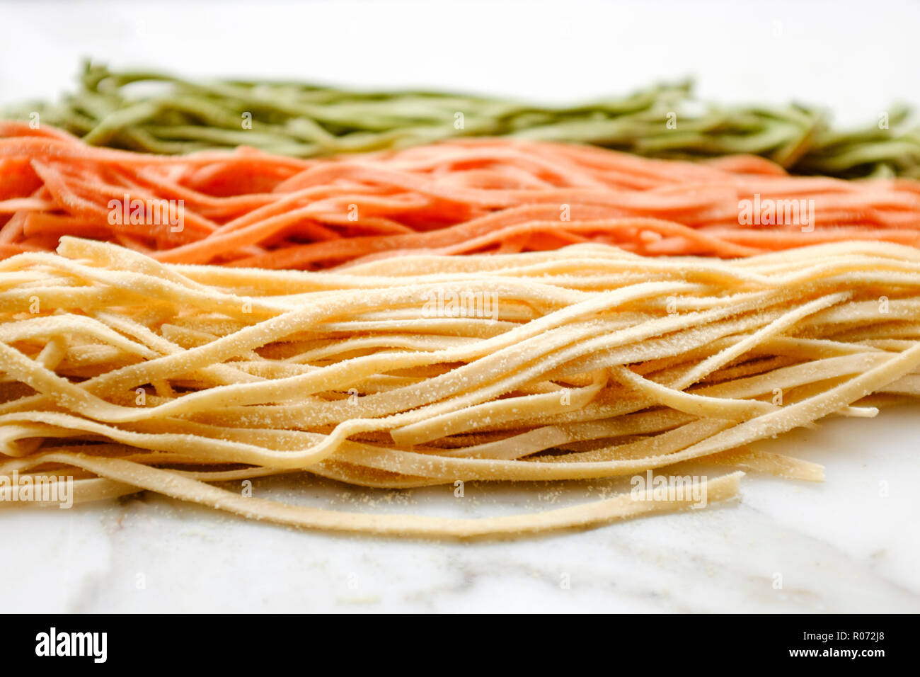 Fresh pasta dusted in semolina laid out in rows on marble bench ready ...