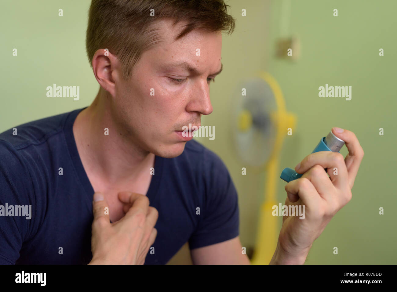 Young handsome man using asthma inhaler at home Stock Photo - Alamy