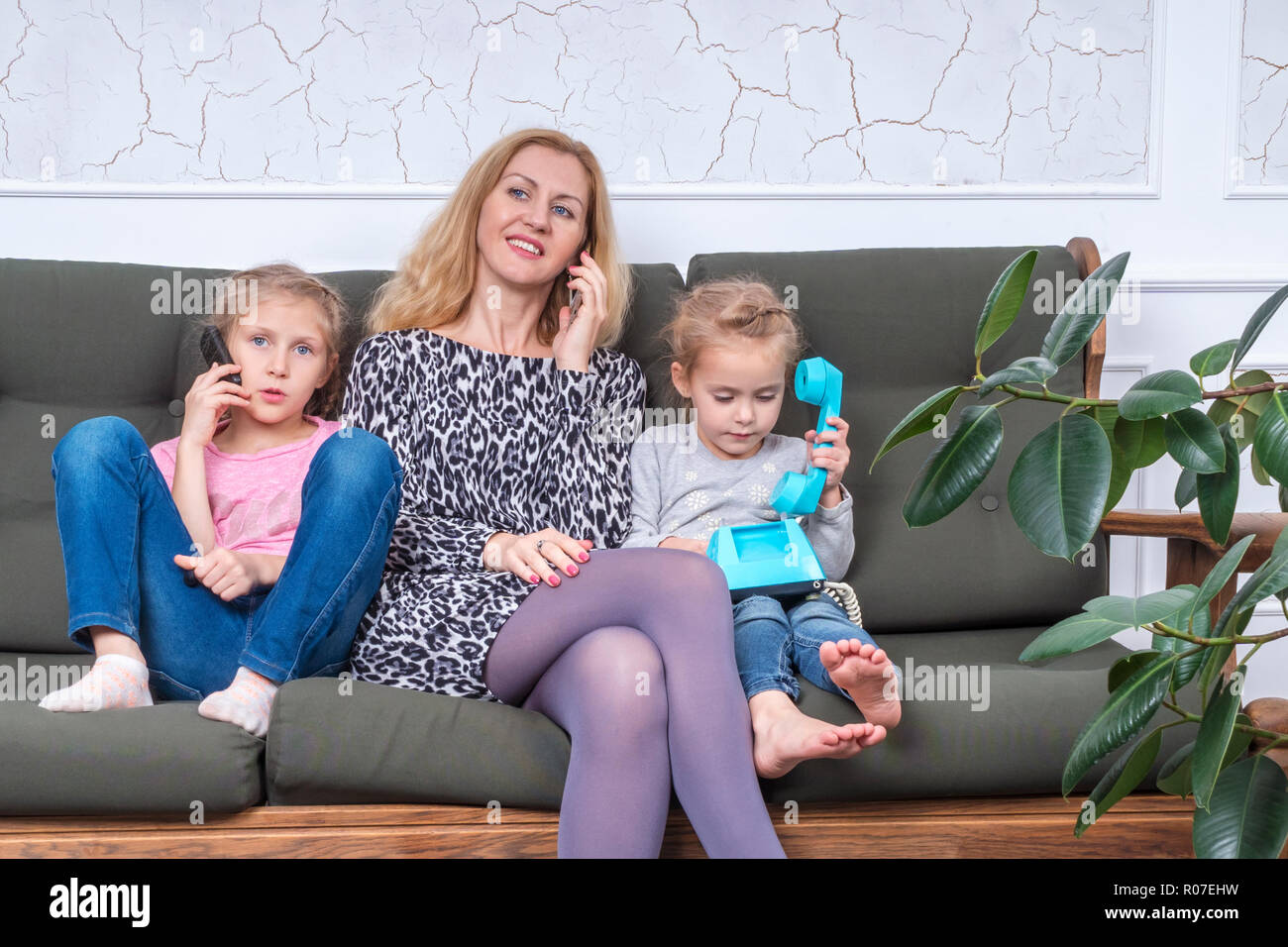 Family mother and two daughters talking on the phones of different ...