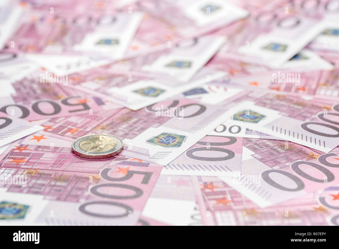 two euro coin on a background of paper money with a face value of five ...
