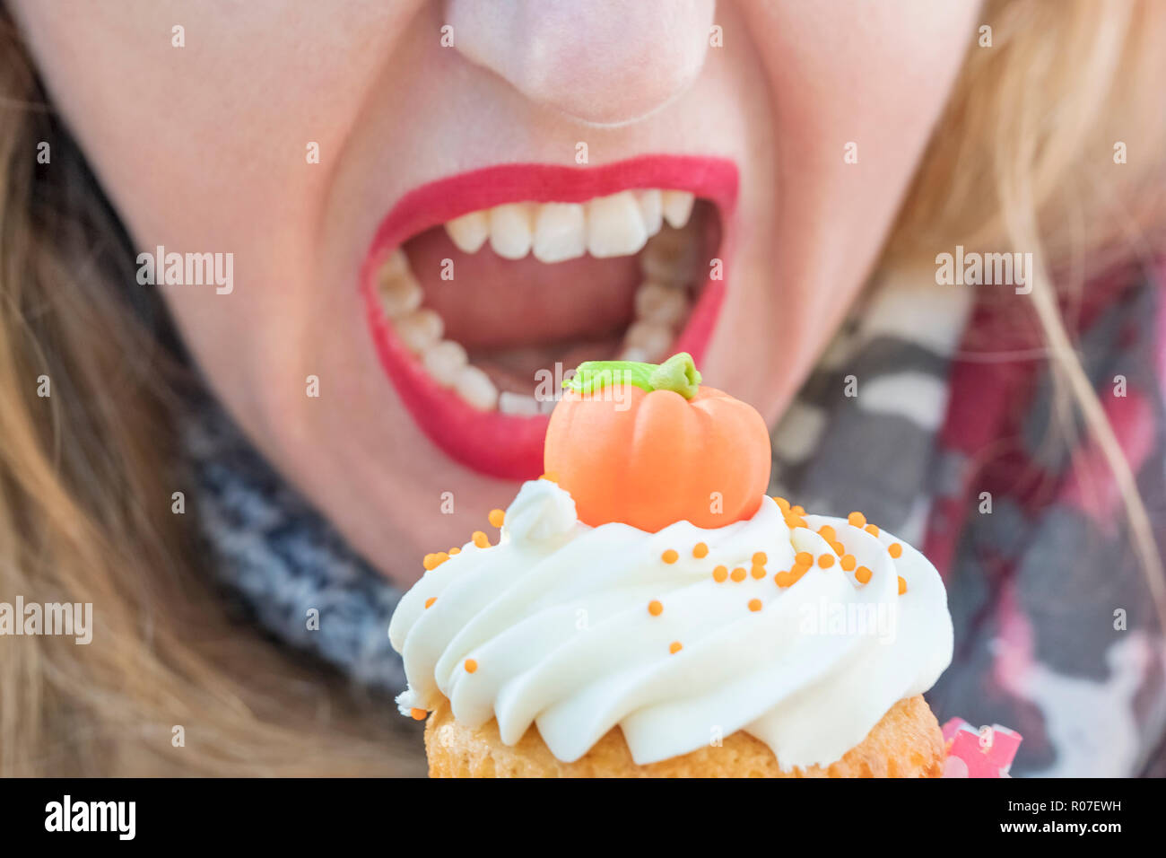 woman opened her mouth to bite a cake in the shape of a pumpkin Stock ...