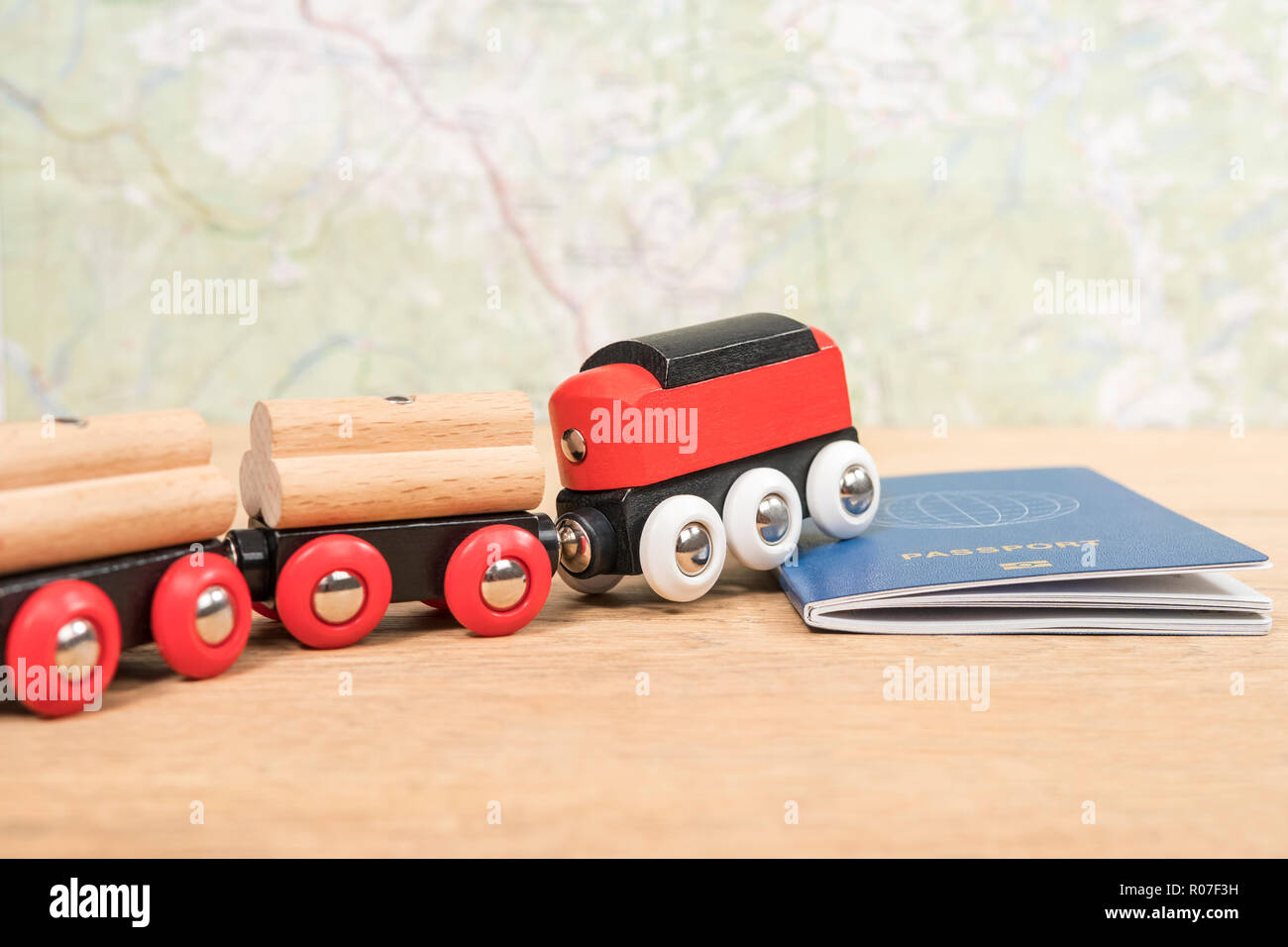red toy train runs over a biometric passport lying on an old wooden ...