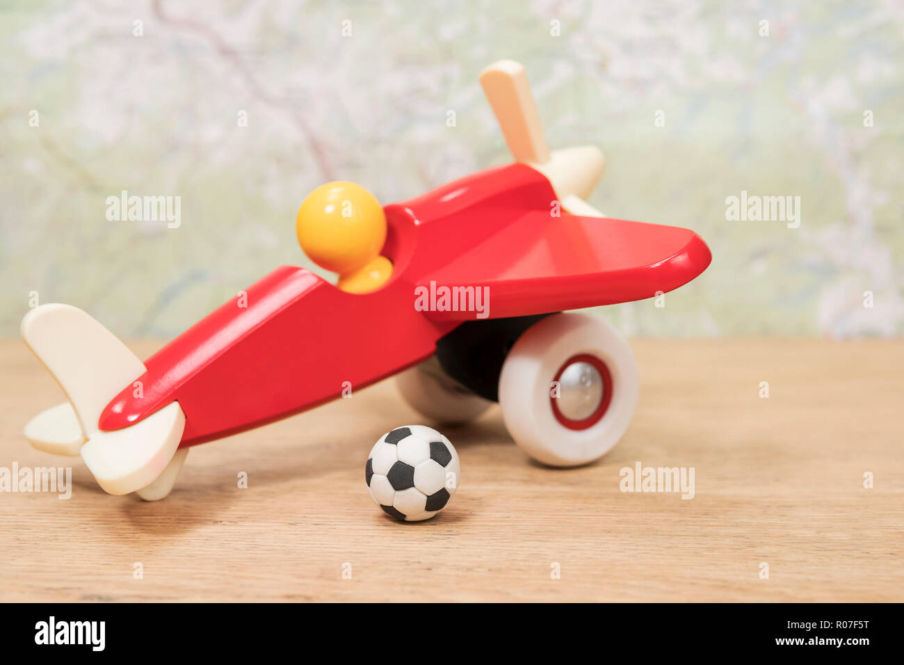 miniature soccer ball at a toy plane lying on a wooden table on a ...