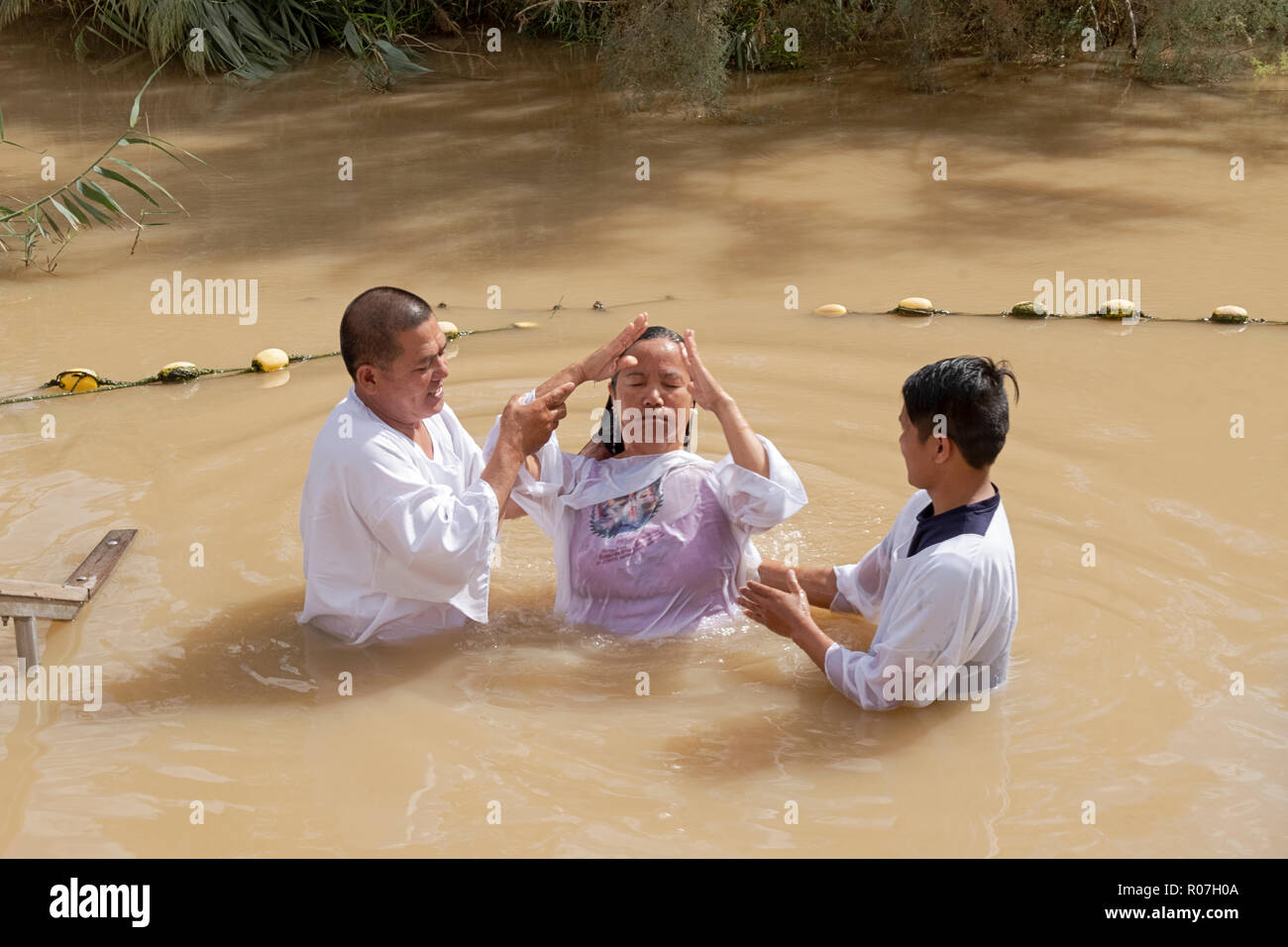 A visitor from the Philippines gets baptized in the Jordan River where ...