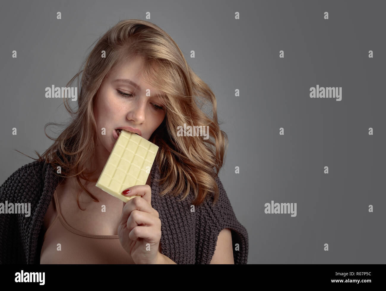 Sad young beautiful woman eating white chocolate. Young blonde with ...
