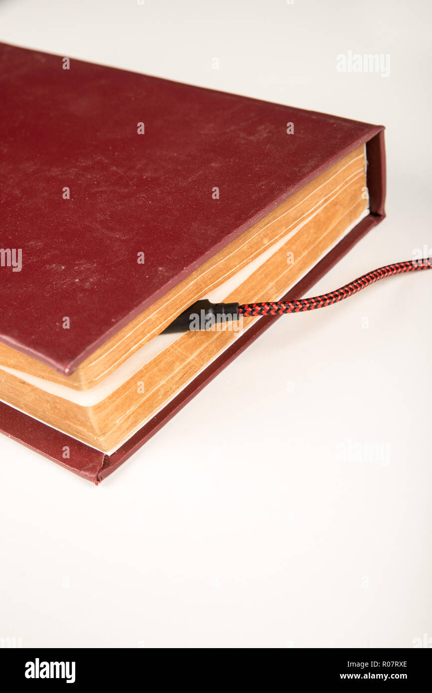 Old book with a battery charging cable, a concept of analog versus ...