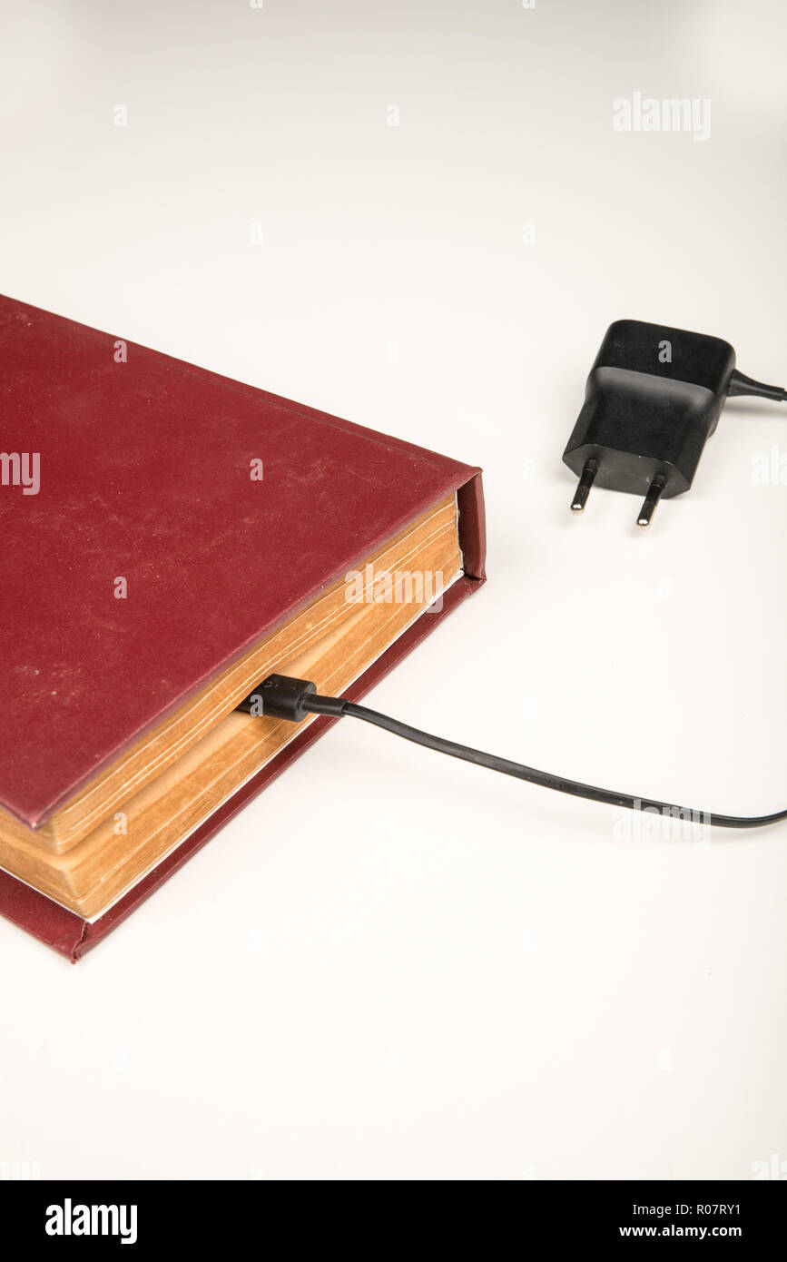 Old book with a battery charging cable, a concept of analog versus ...