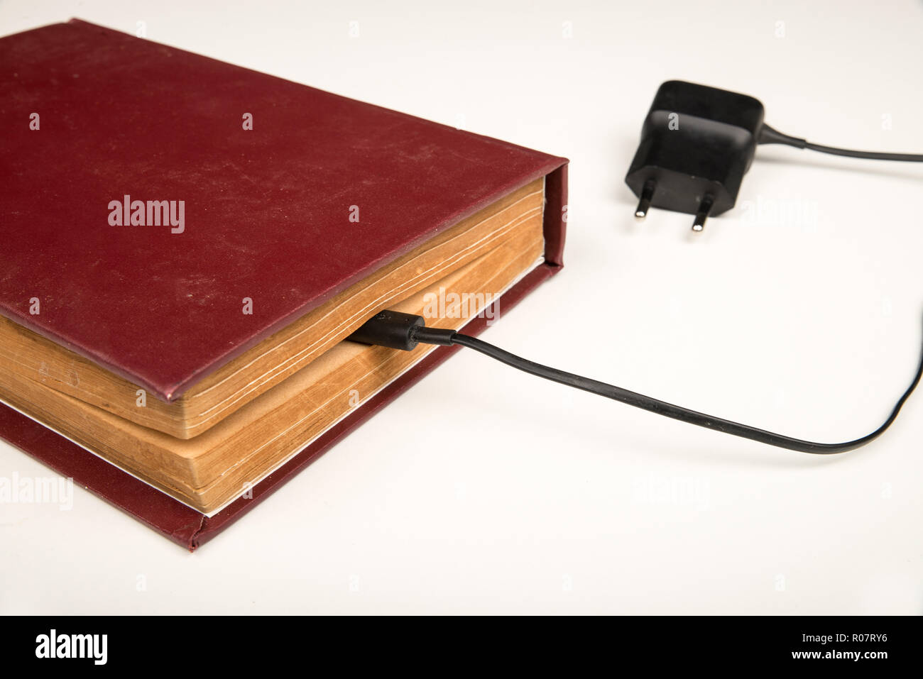 Old book with a battery charging cable, a concept of analog versus ...