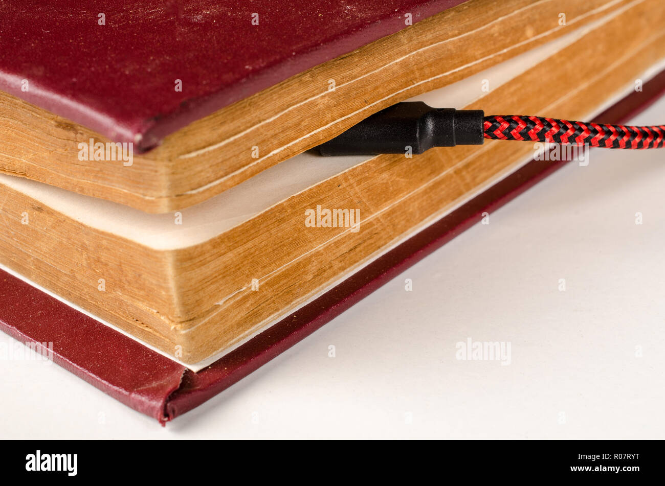 Old book with a battery charging cable, a concept of analog versus ...