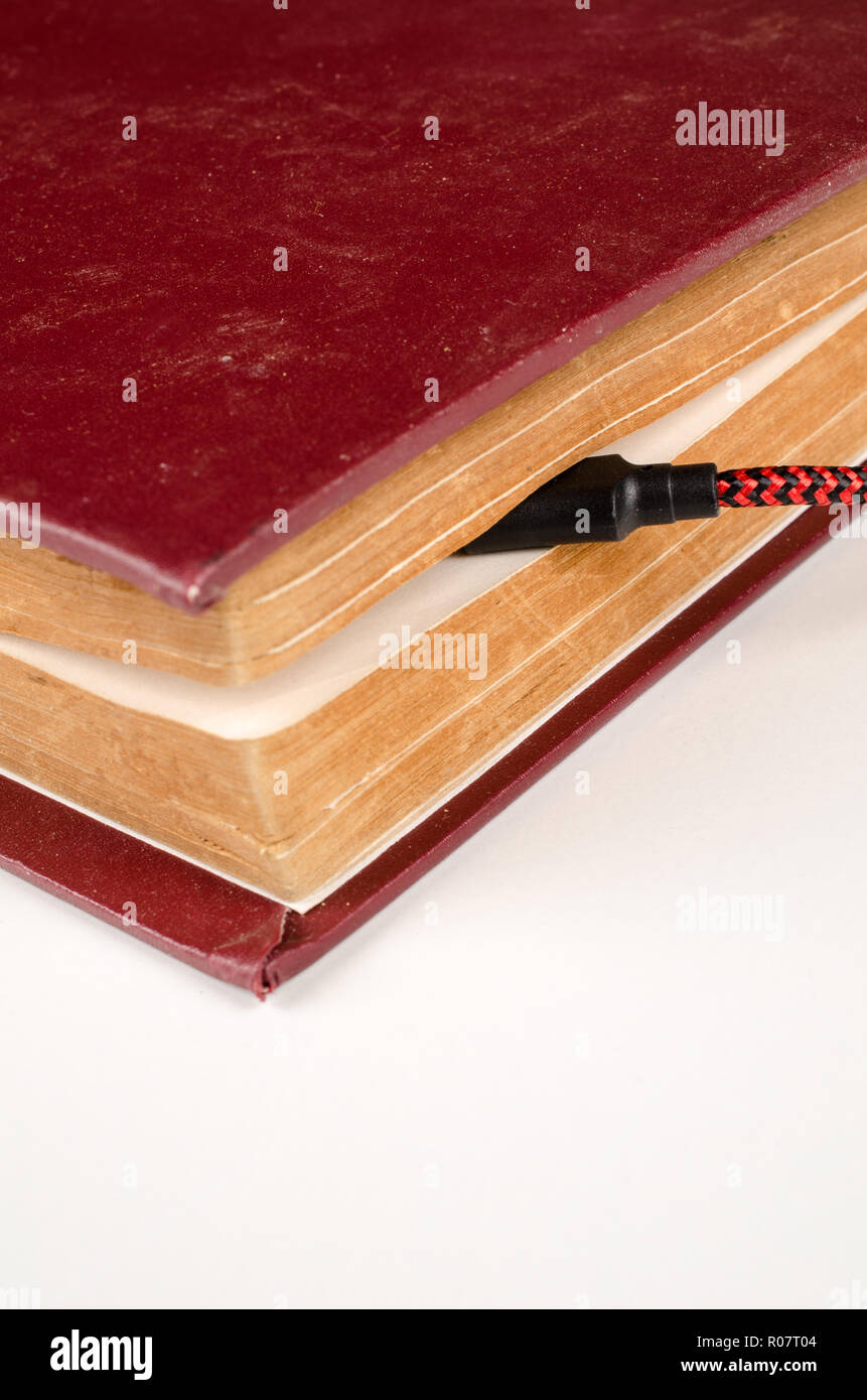 Old book with a battery charging cable, a concept of analog versus ...