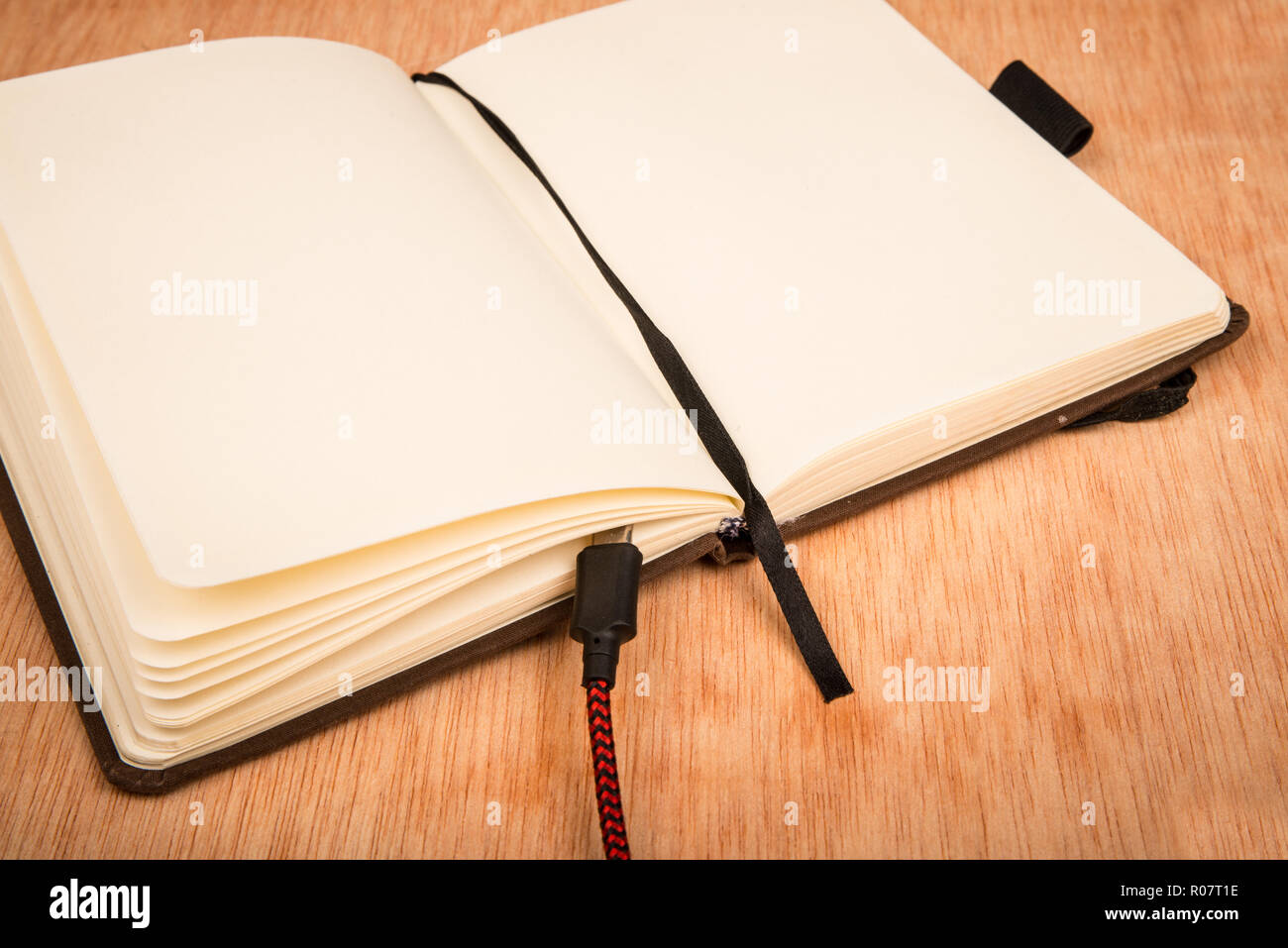 Small paper notebook with a battery charging cable, a concept of analog ...