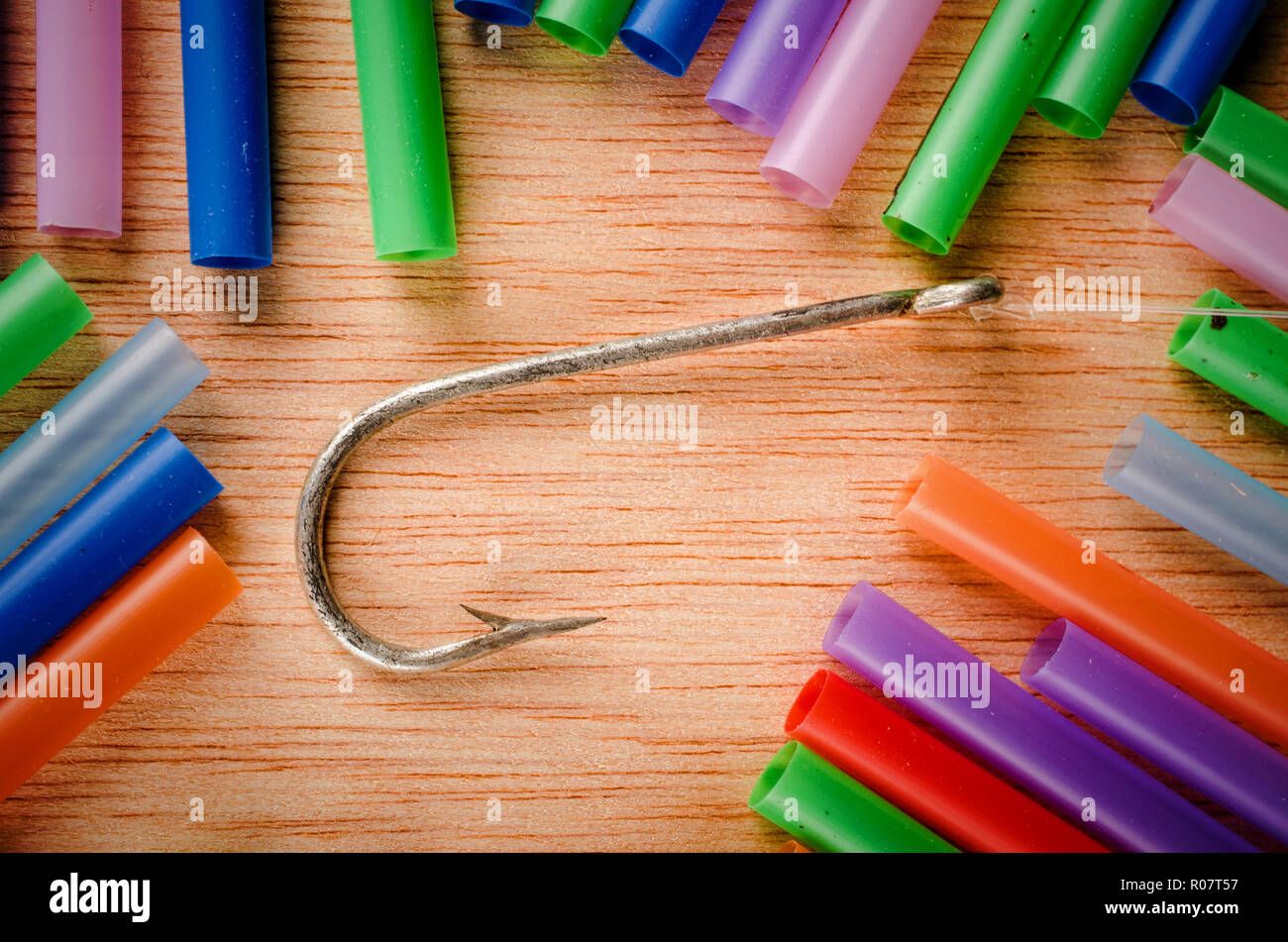 Fishing hook surrounded by drinking straws, a concept of the pollution ...