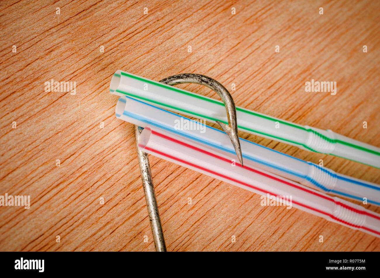 Fishing hook surrounded by drinking straws, a concept of the pollution ...