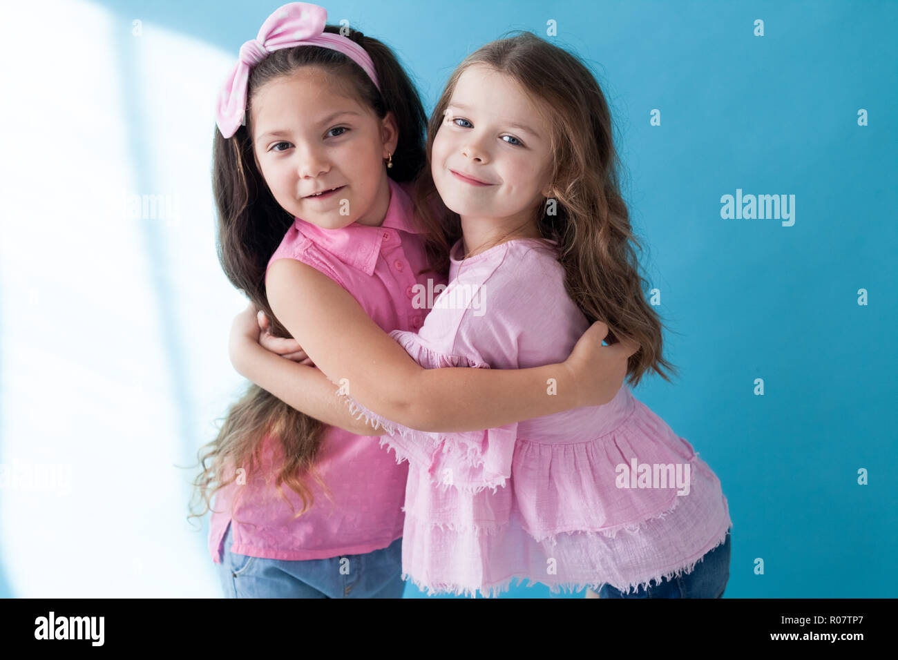 two little girls girlfriends together on blue background Stock Photo ...