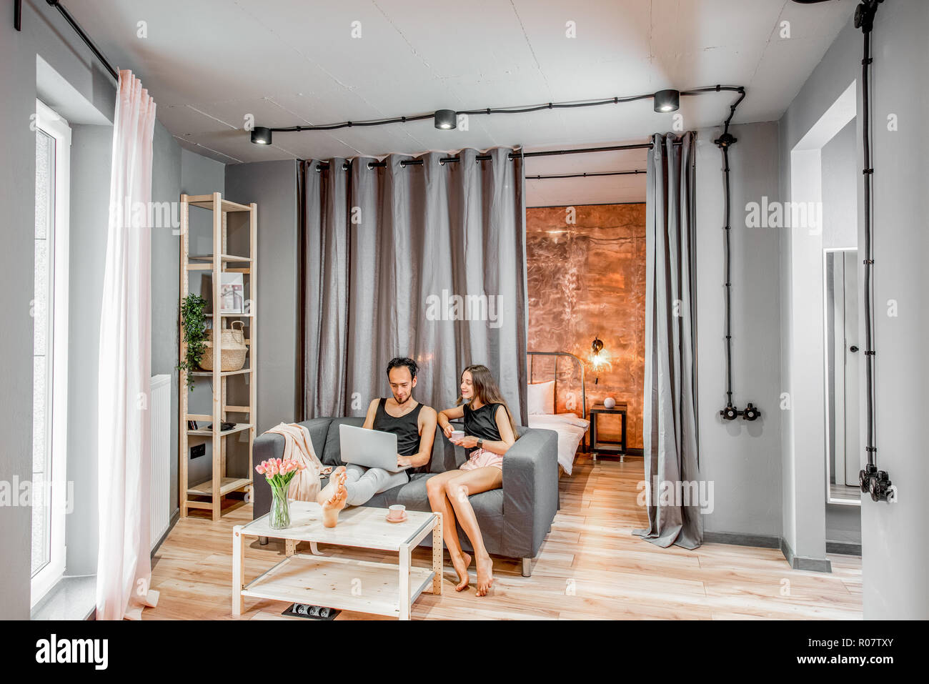 Modern living room with young lovely couple on the couch at their ...