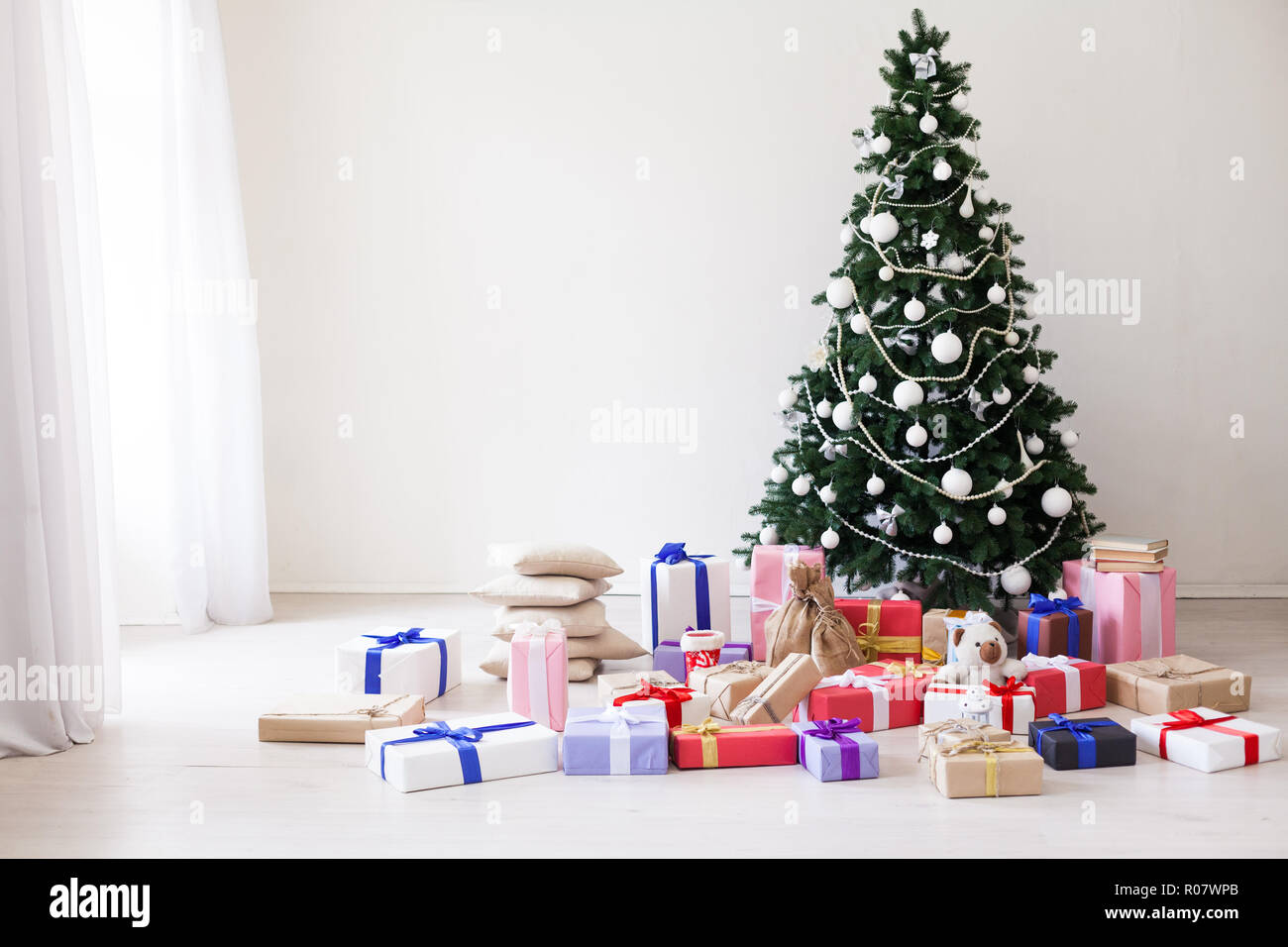 Christmas tree with Christmas gifts in white room Stock Photo - Alamy
