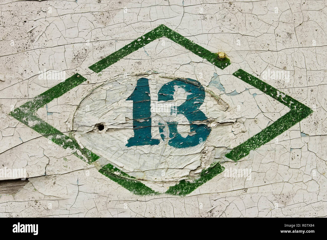 Number thirteen. Sign, put paint on the old wooden painted surface ...