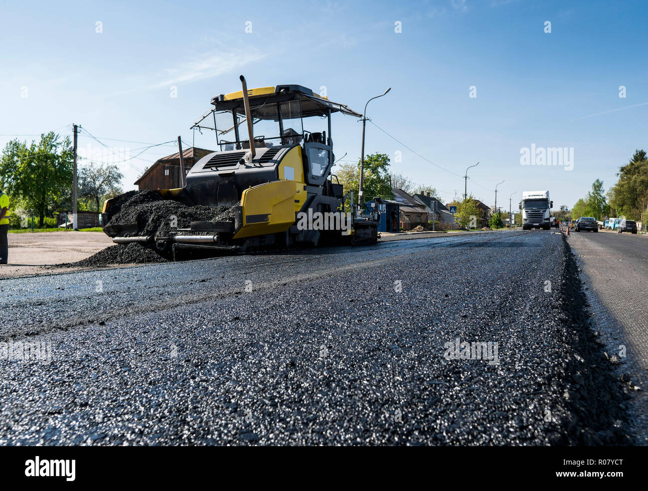 Worker operating asphalt paver machine during road construction and ...