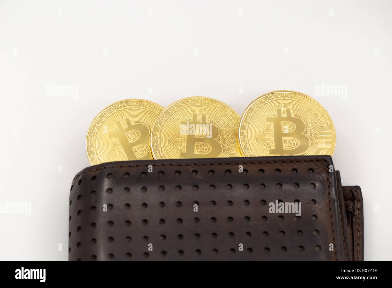 Three Bitcoin tokens coming out of a wallet, on white background ...