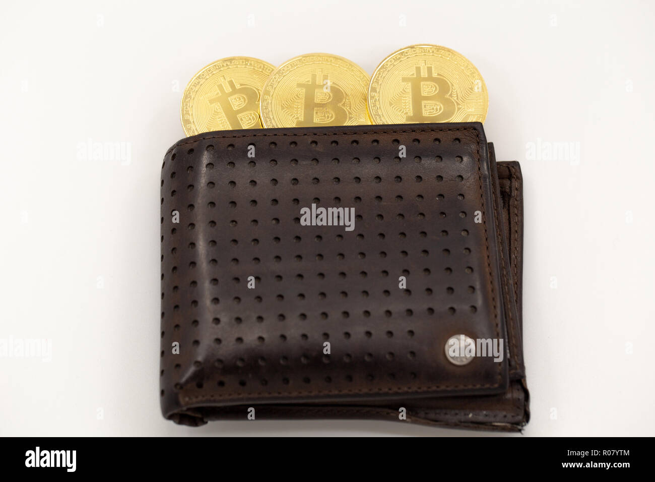 Three Bitcoin tokens coming out of a wallet, on white background ...
