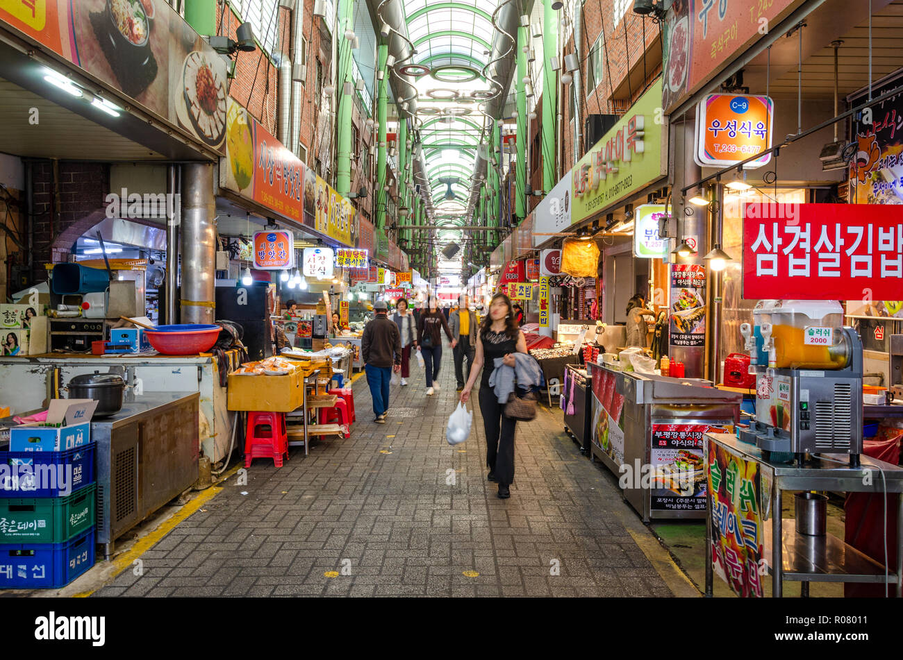 A view along a busy alley lined with stalls in the indoor market ...