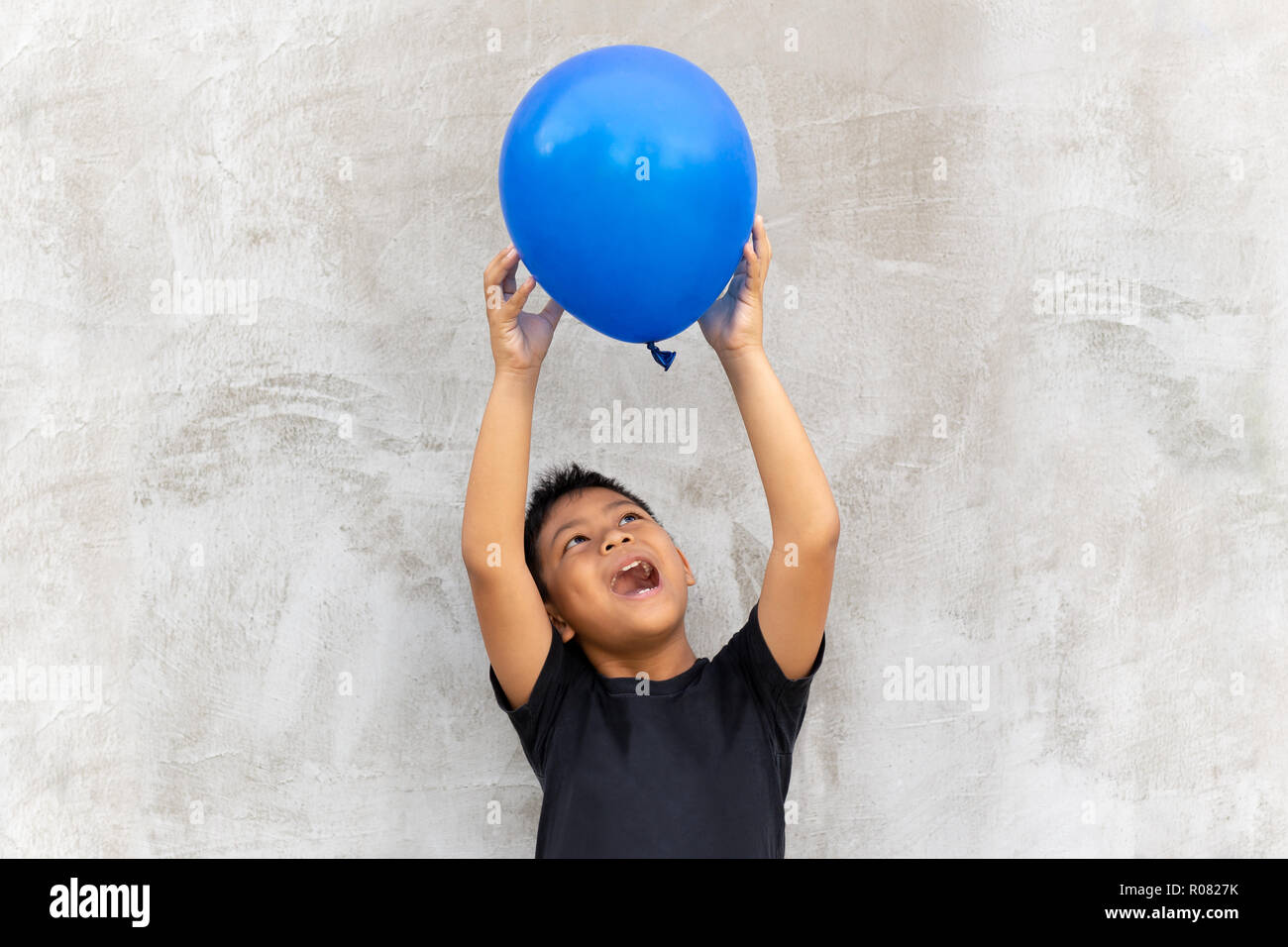 Asian boy play catches balloon on grey background Stock Photo - Alamy