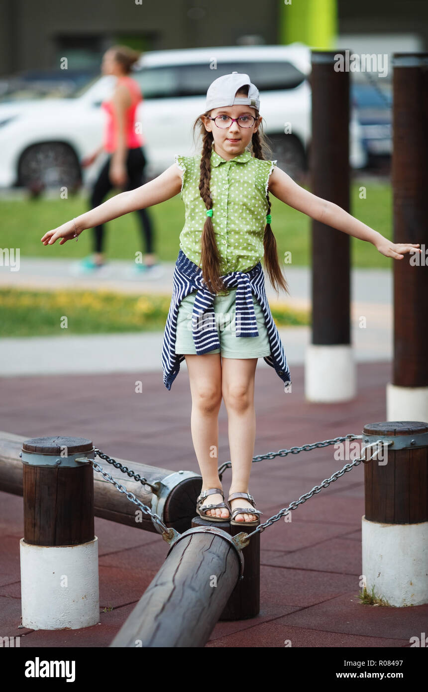 Little girl walking on a log in the playground. Child balancing on a ...