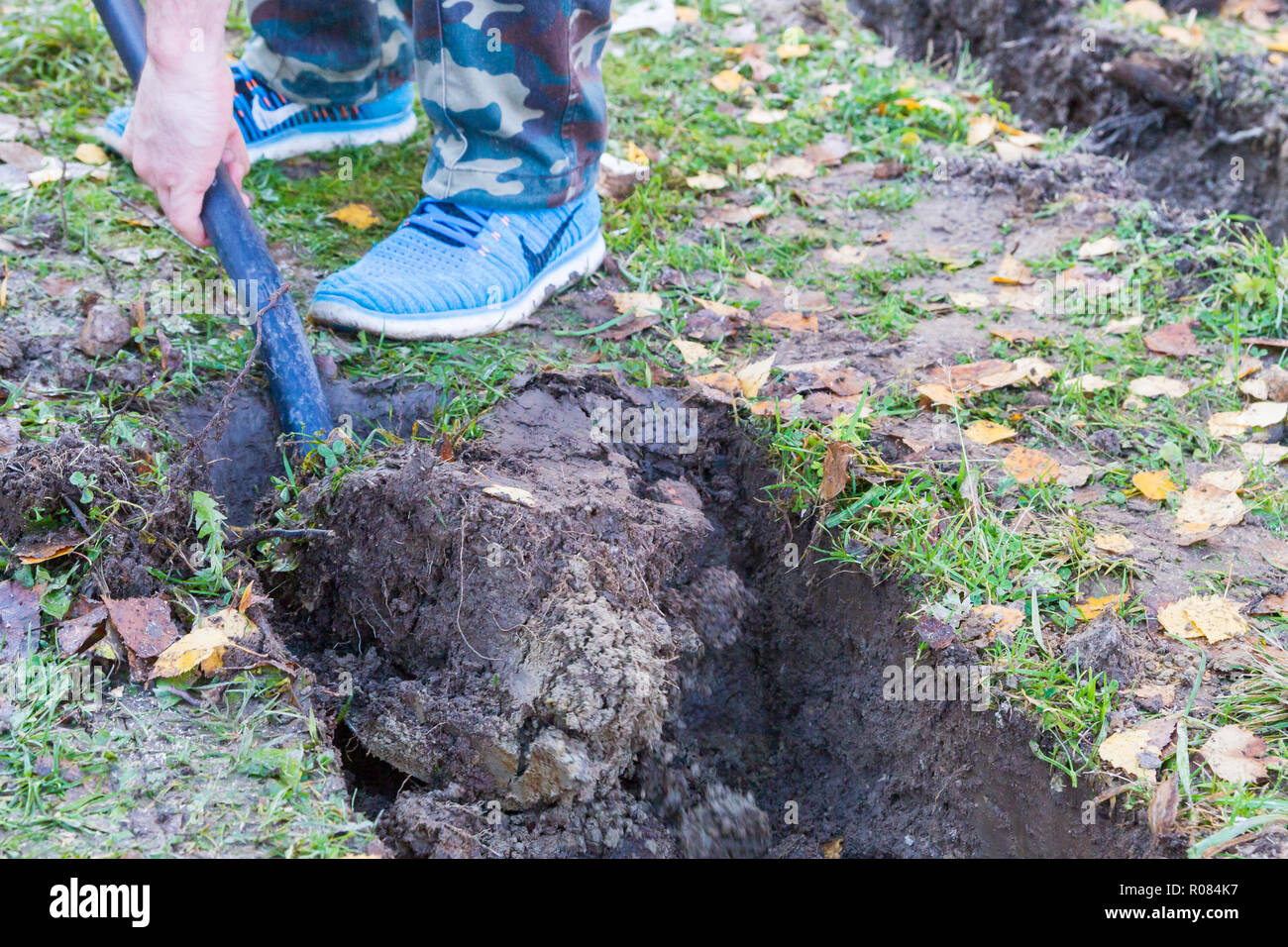 Man digging a ditch with a shovel in autumn Stock Photo - Alamy