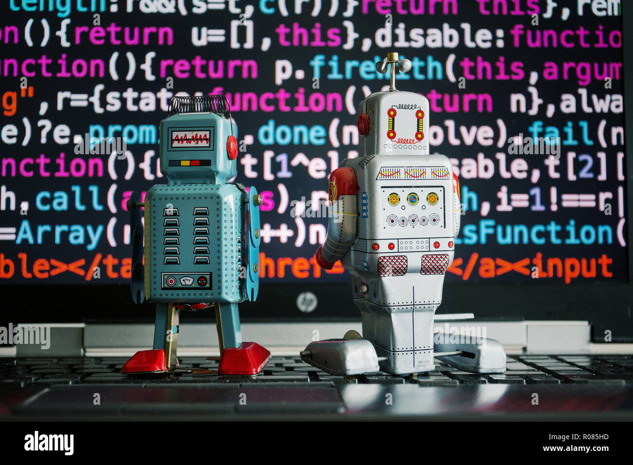 Two robots looking at laptop screen with source code, artificial ...