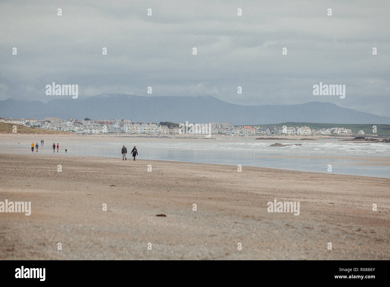 People walking along Cymyran beach, Rhosneigr, Anglesey, North Wales ...