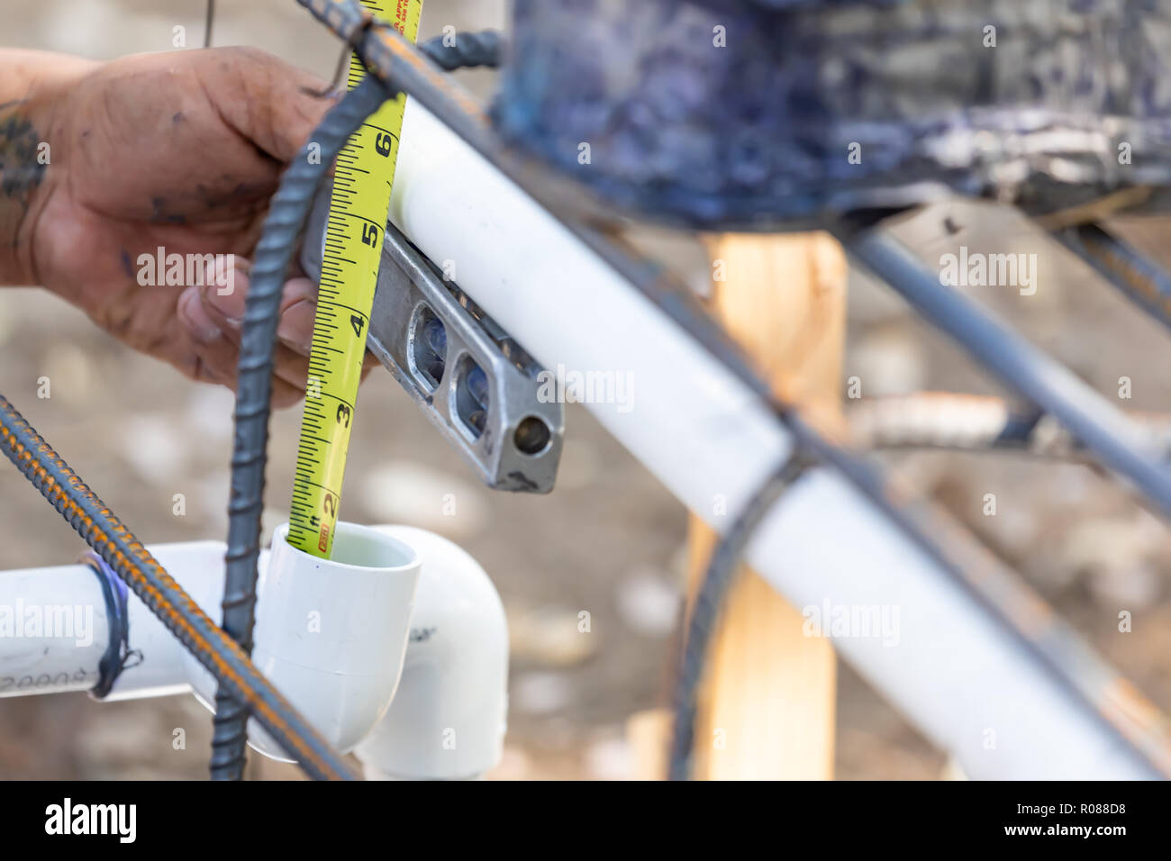 Plumber Using Level And Tape Measure While Installing PVC Pipe At ...