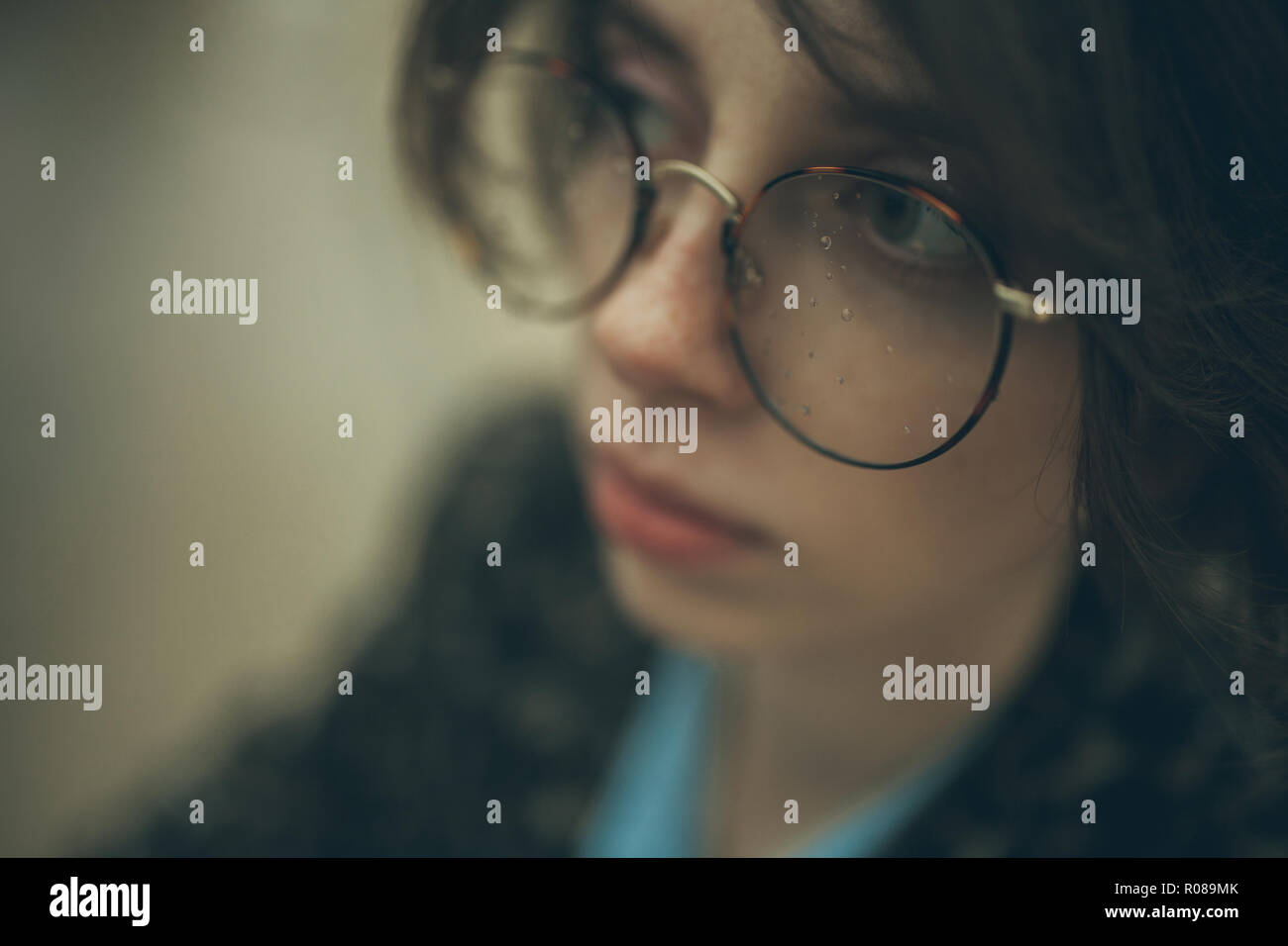 Portrait of pensive woman with misted glasses and droplets of water on ...