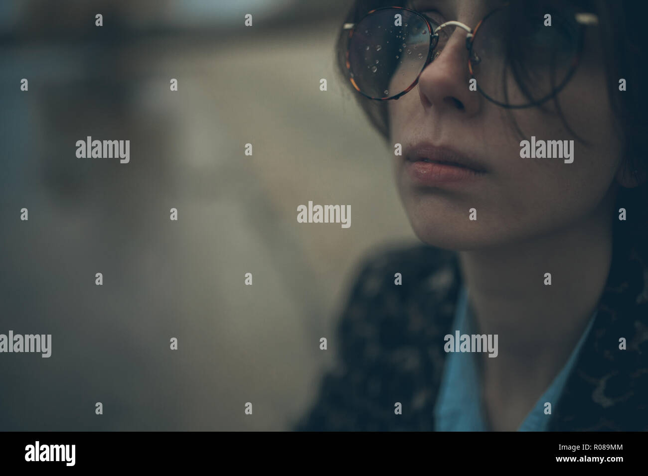 Portrait of pensive woman with misted glasses and droplets of water on ...