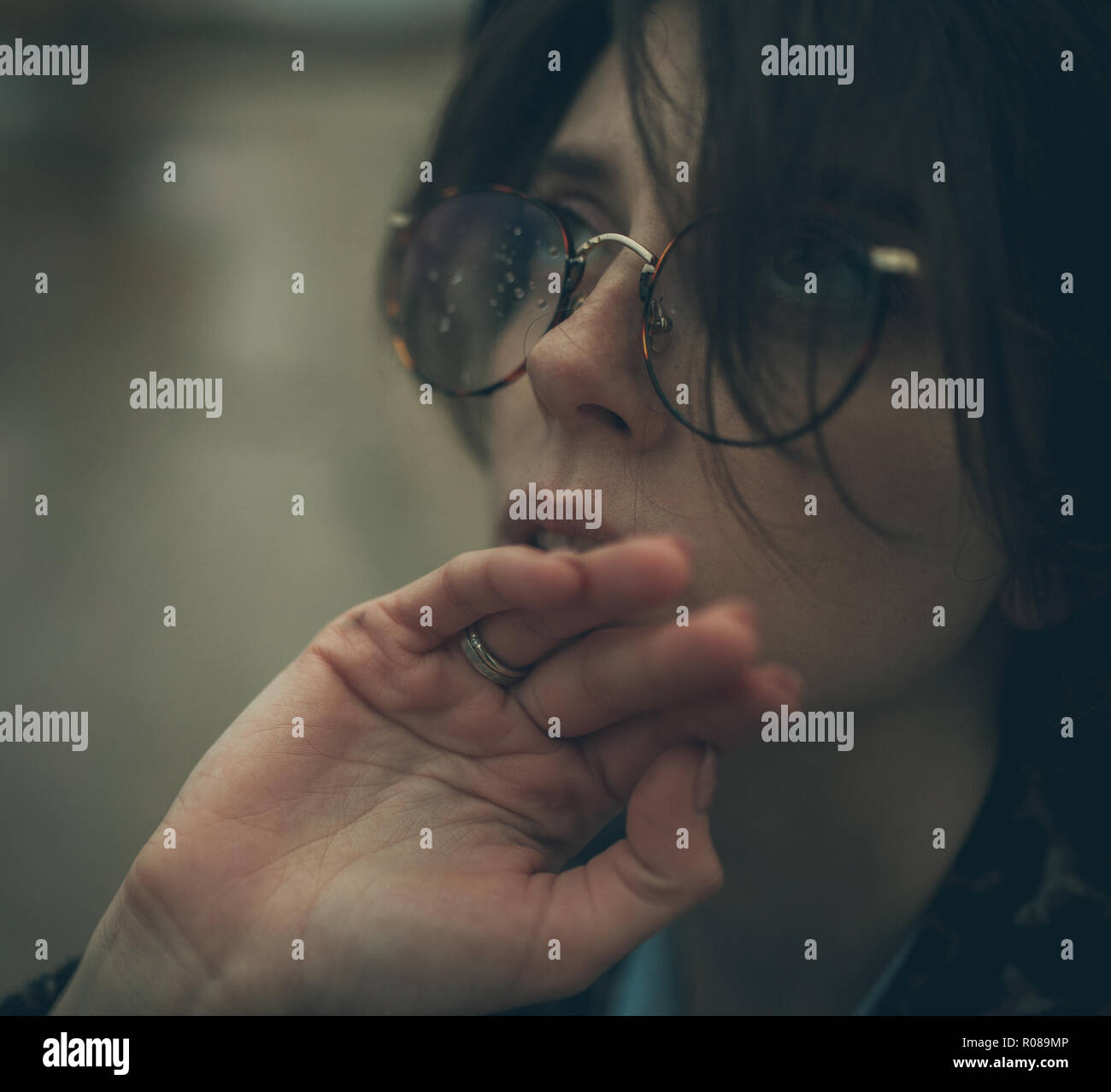Portrait of pensive woman with misted glasses and droplets of water on ...