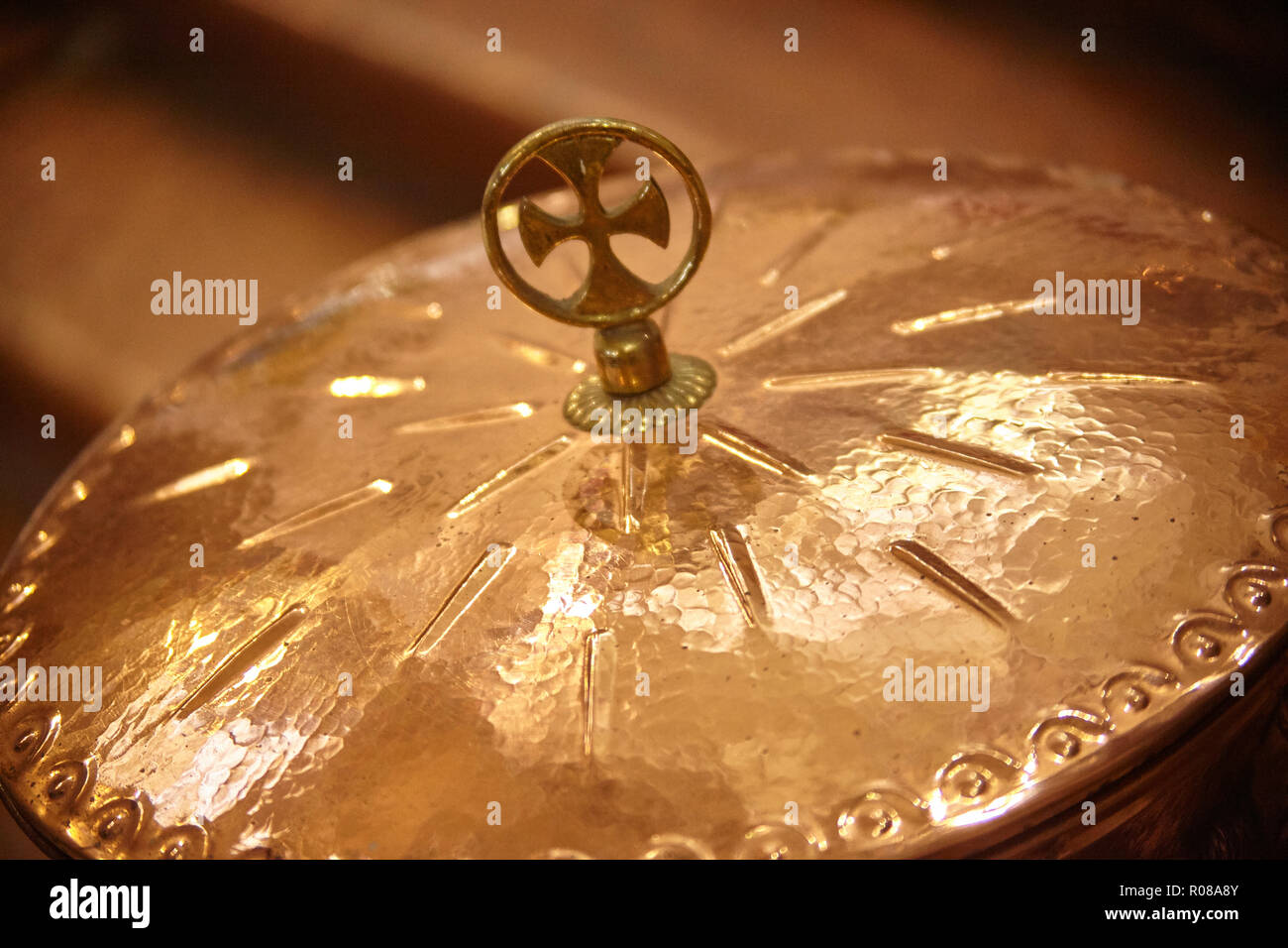Detail of a copper bowl with a cross above used as a liturgical object ...